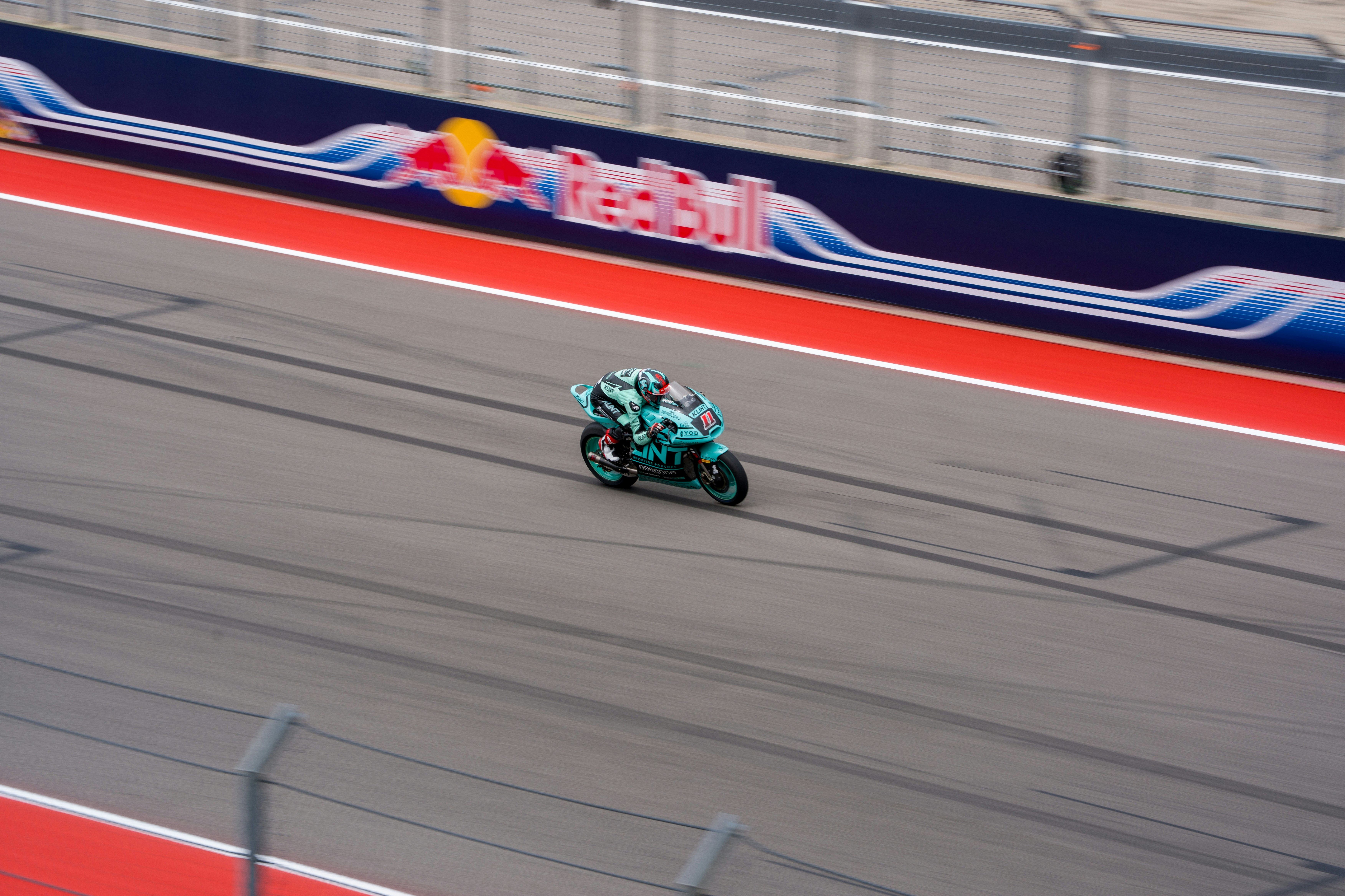 Teal racer glides along the oval curve with motion blur