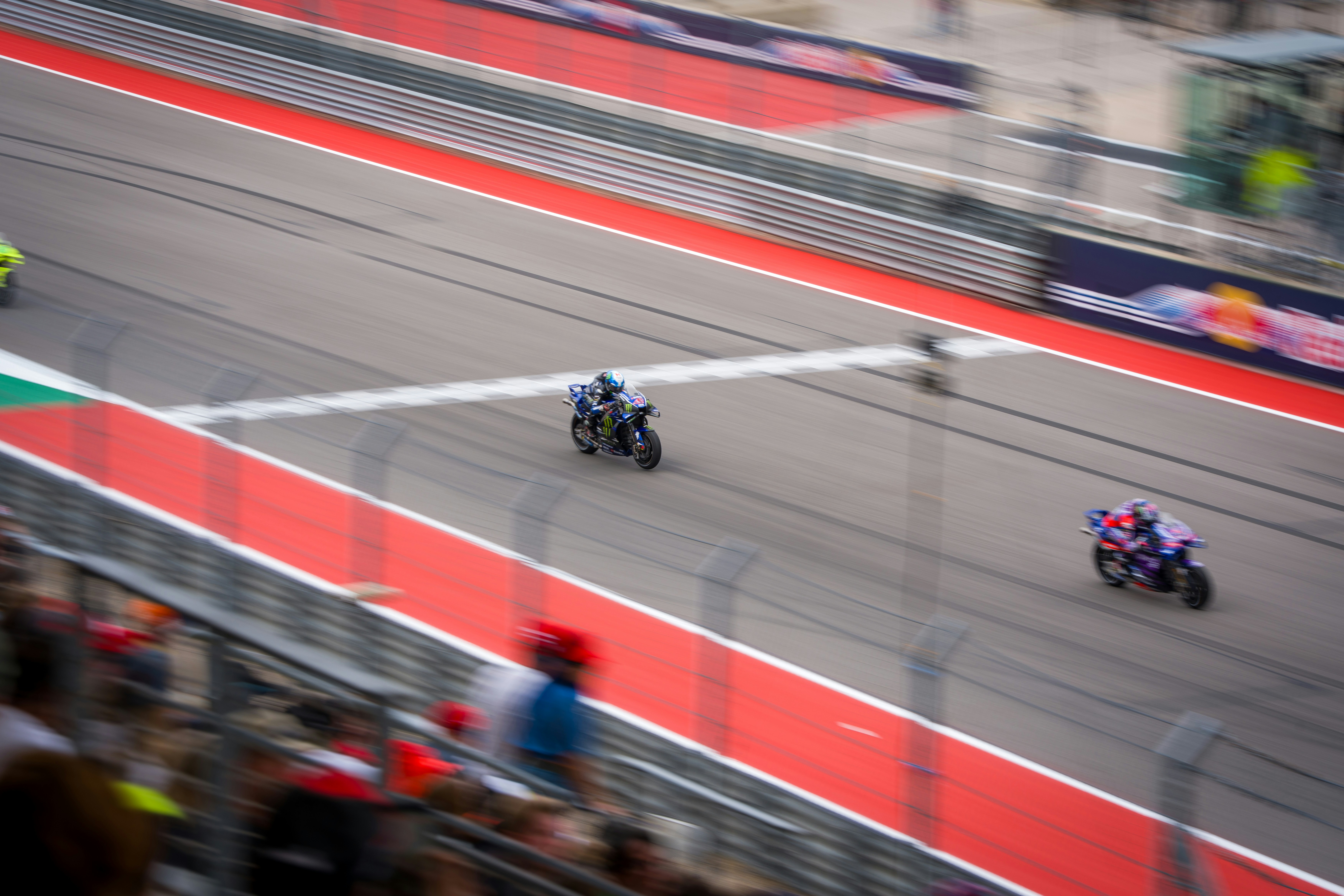 Blurred speed: two riders carve the track under a blur of color and spectators