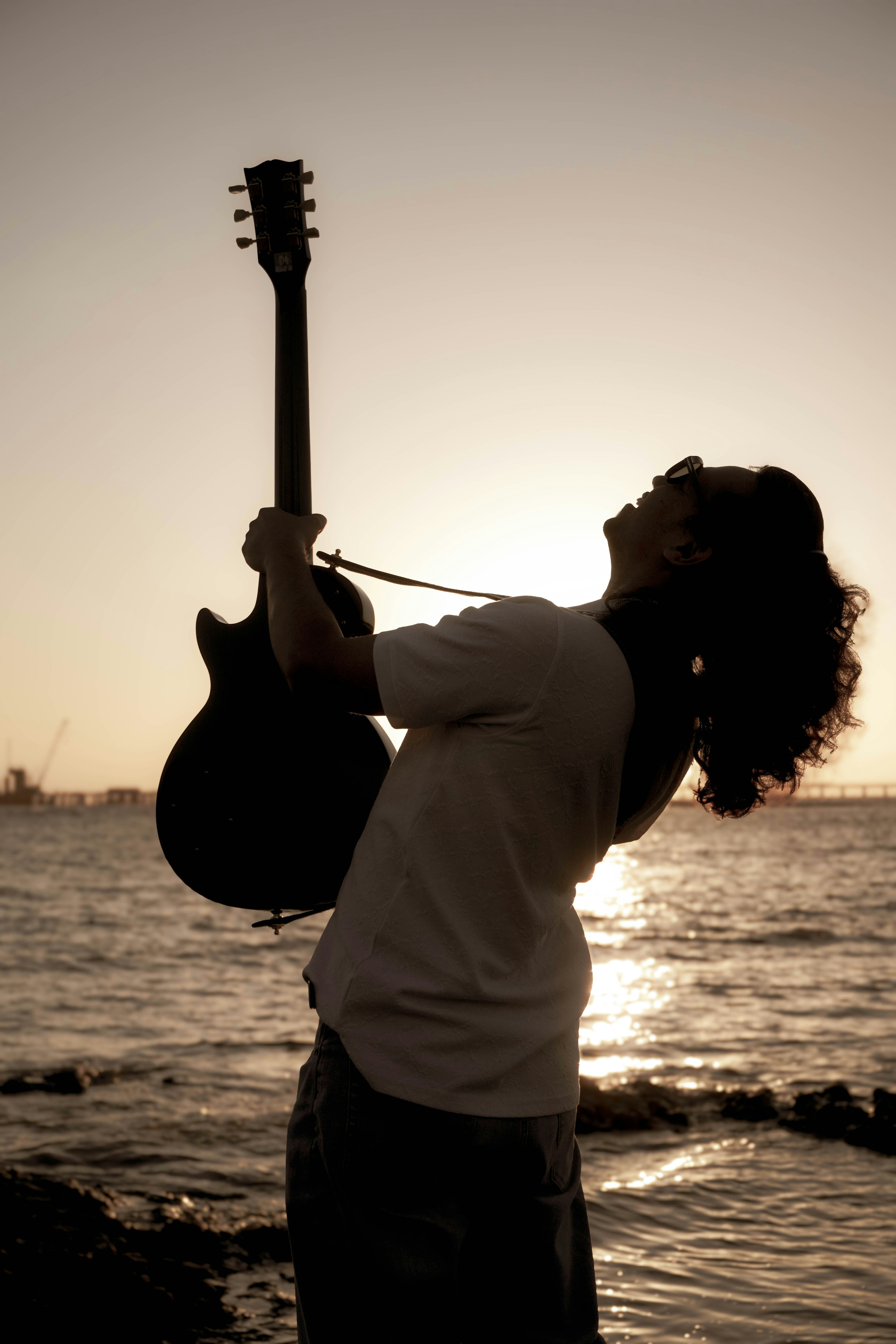 Sunset Serenade: Guitarist Backlit by Golden Tide
