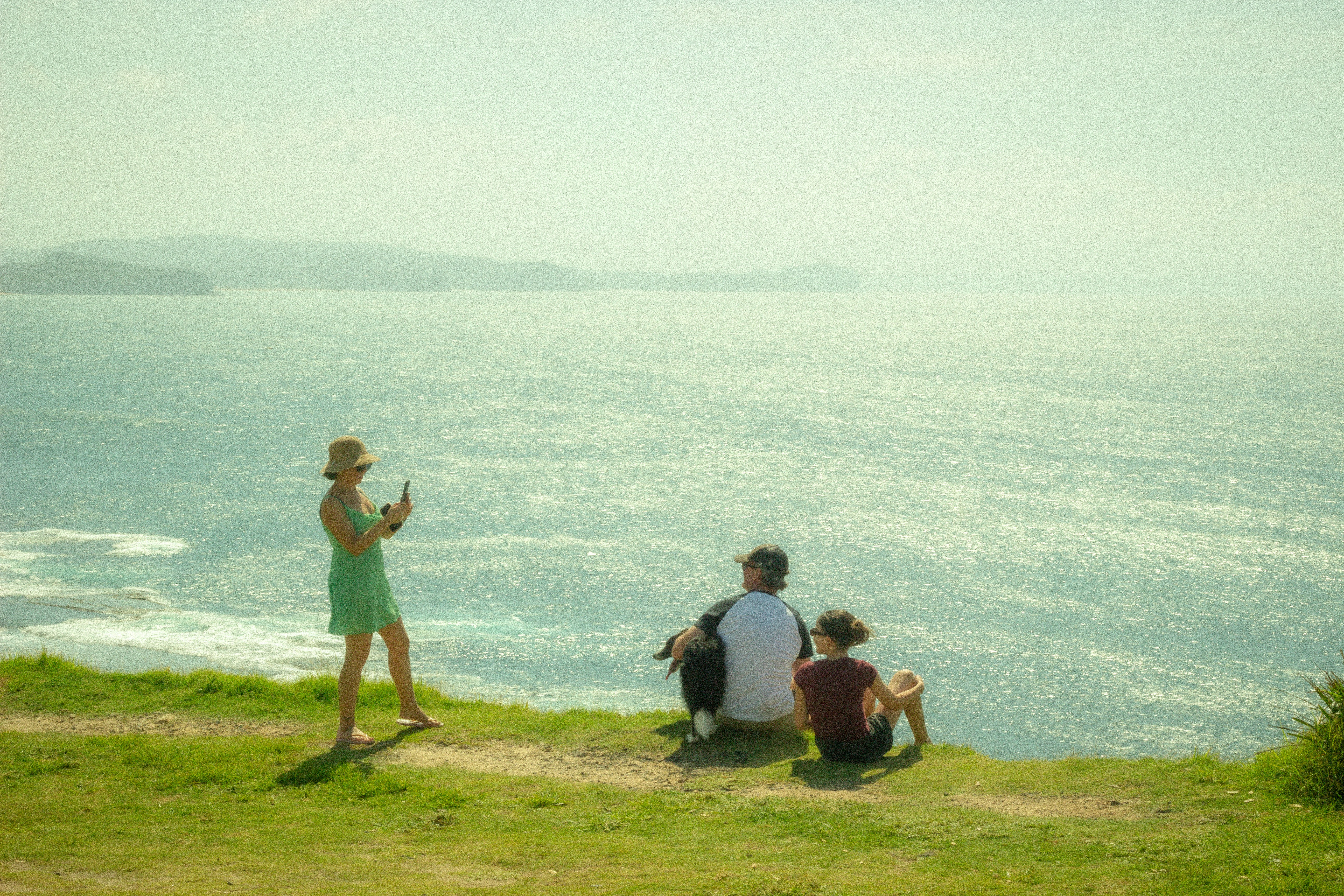 Sunlit Coastal Moment: A lone photographer by the sea