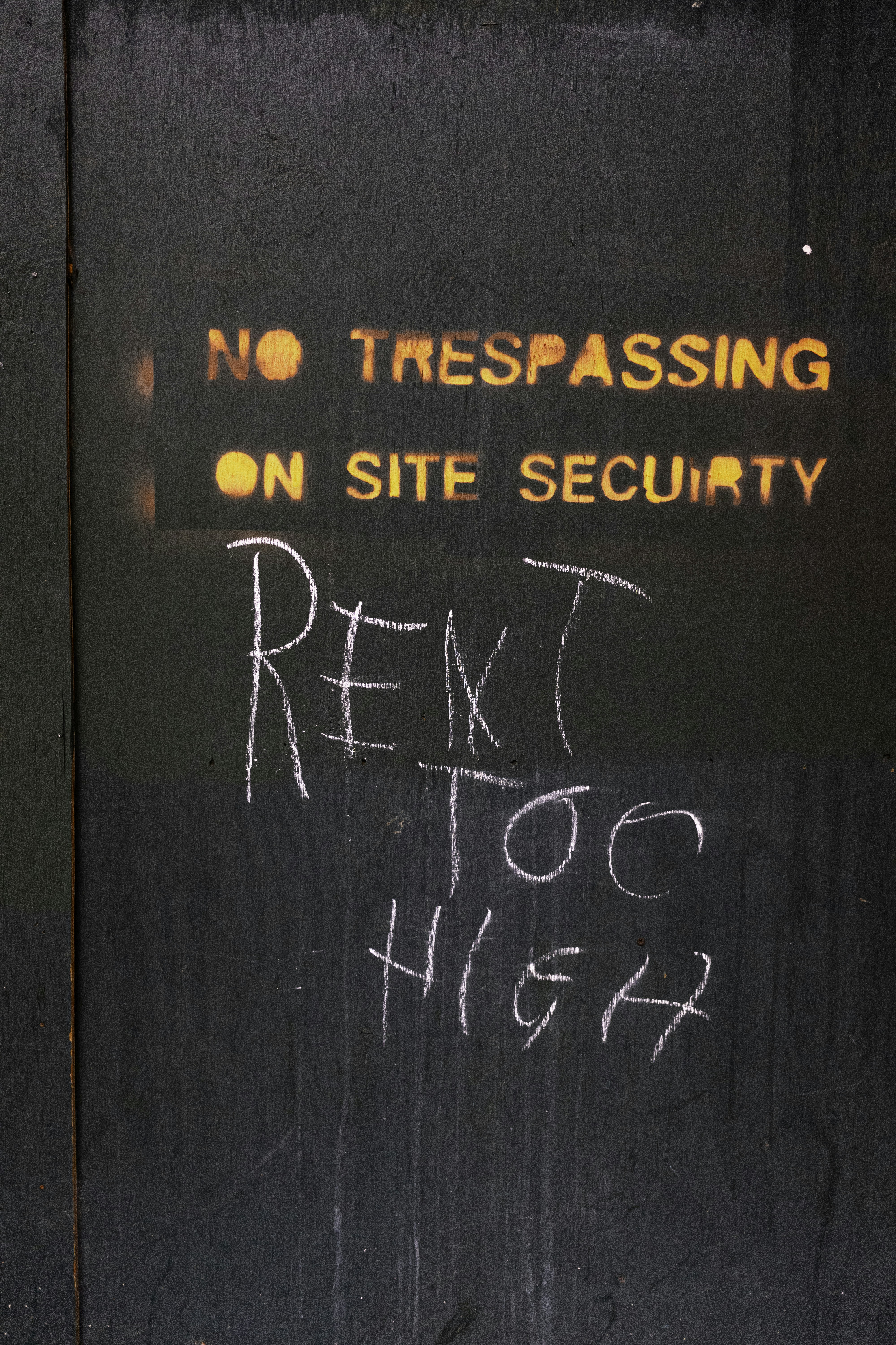 Weathered Gate: Neon Warning and Chalked Graffiti Mark the Metal Door
