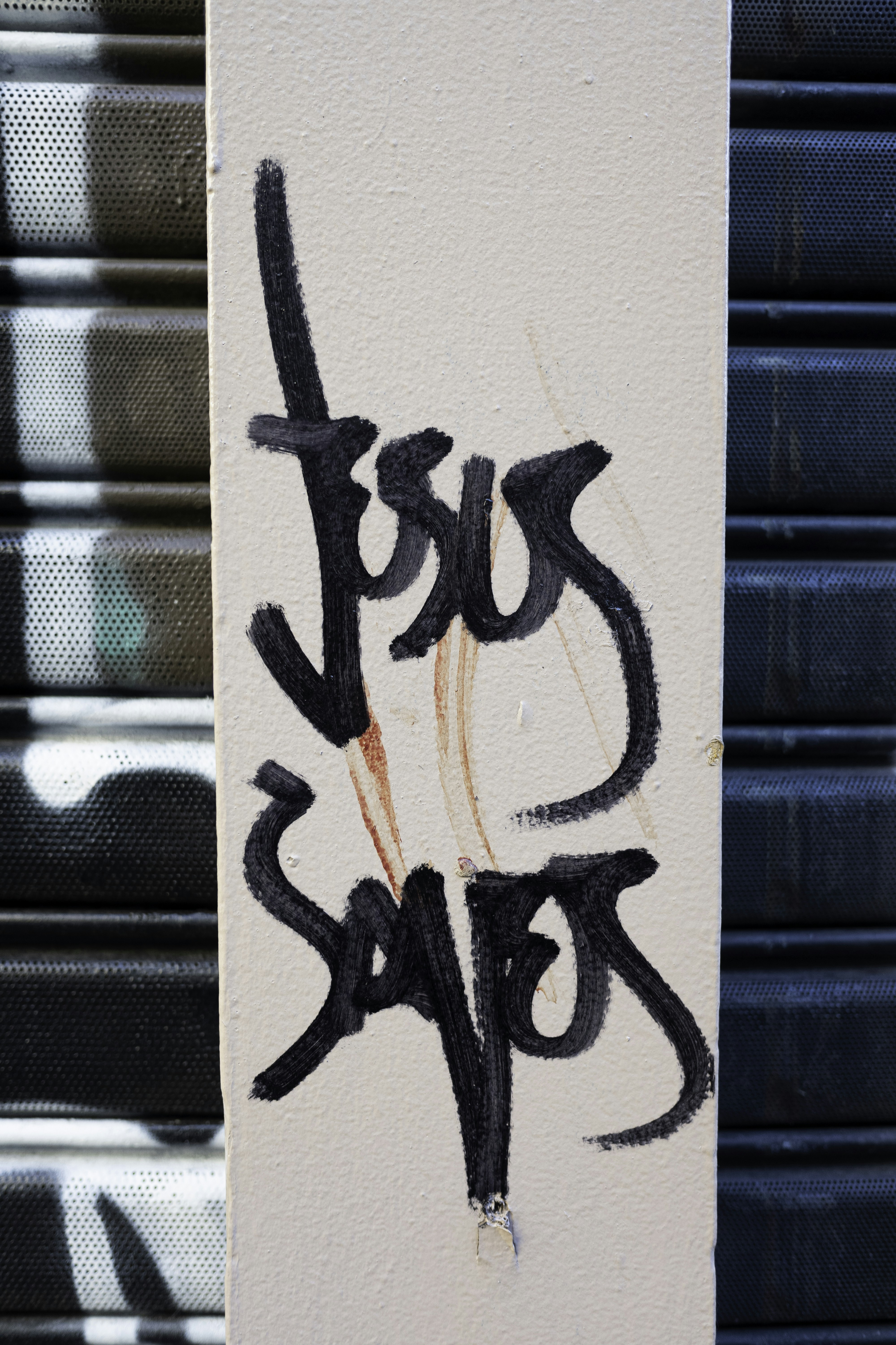 Vertical graffiti centerpiece on a street shutter pillar