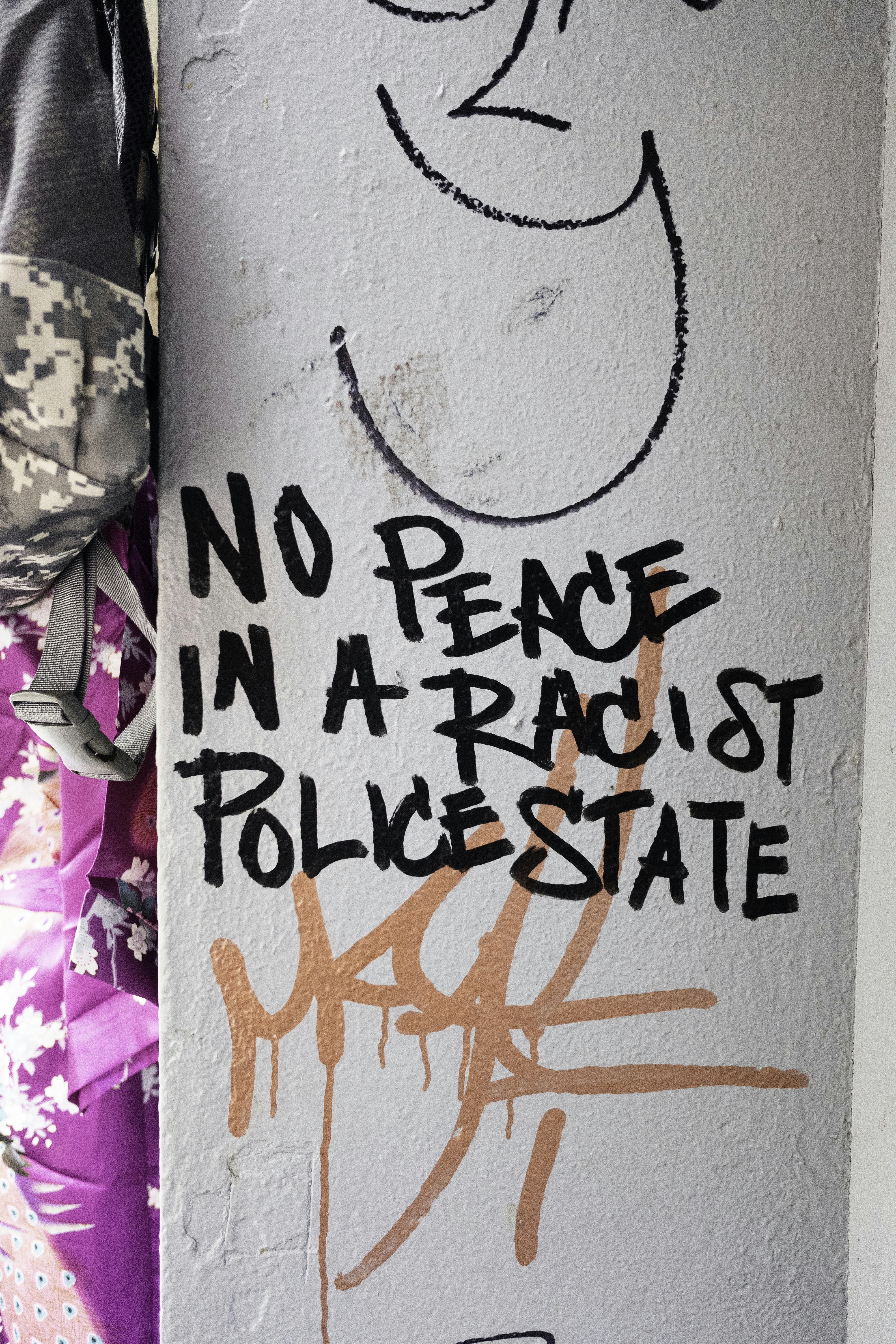Graffiti Message on a Graffitied Column with Backpack Slide