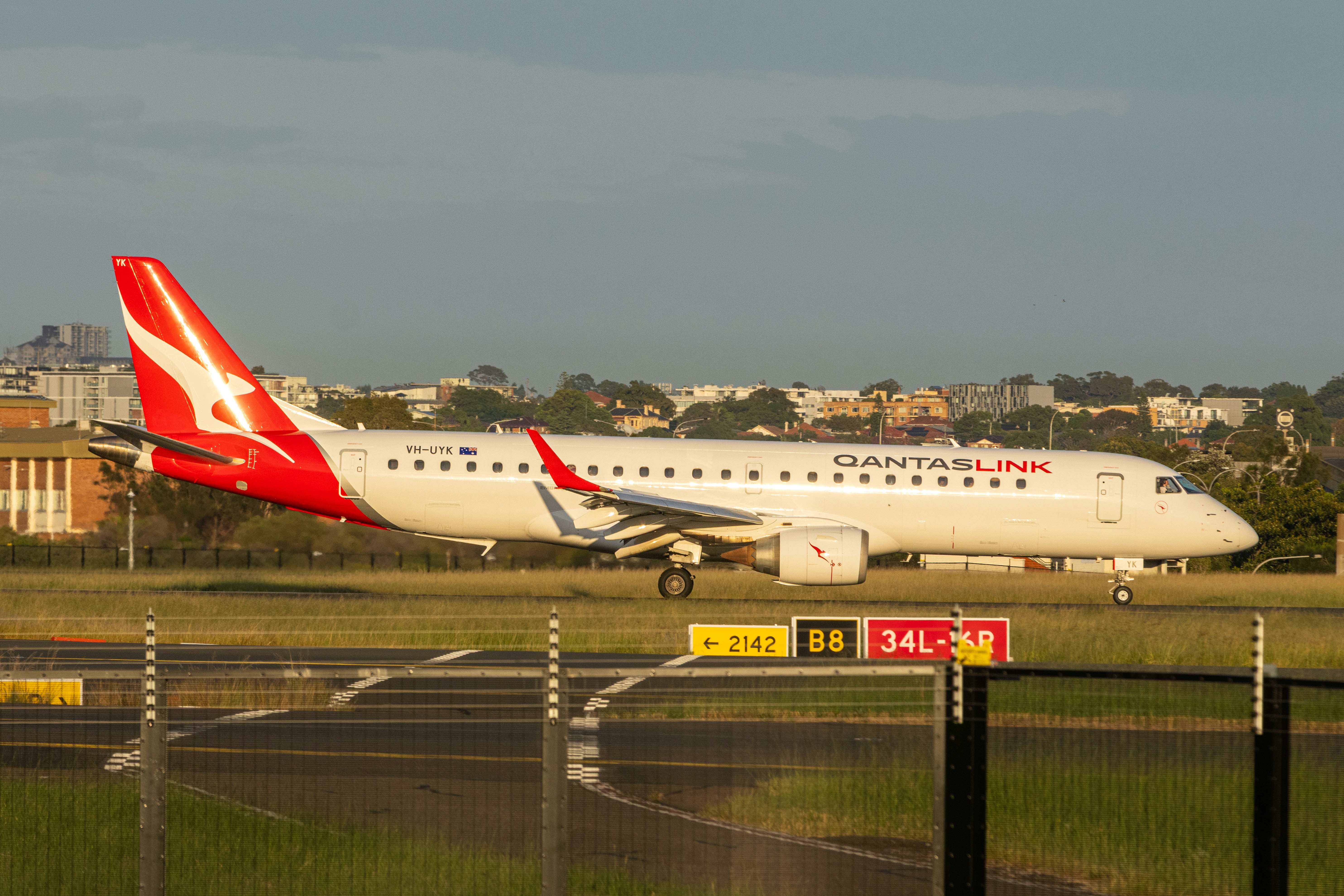 QantasLink Jet at Runway Edge, Sunlit FBO Fence in Sharp Focus