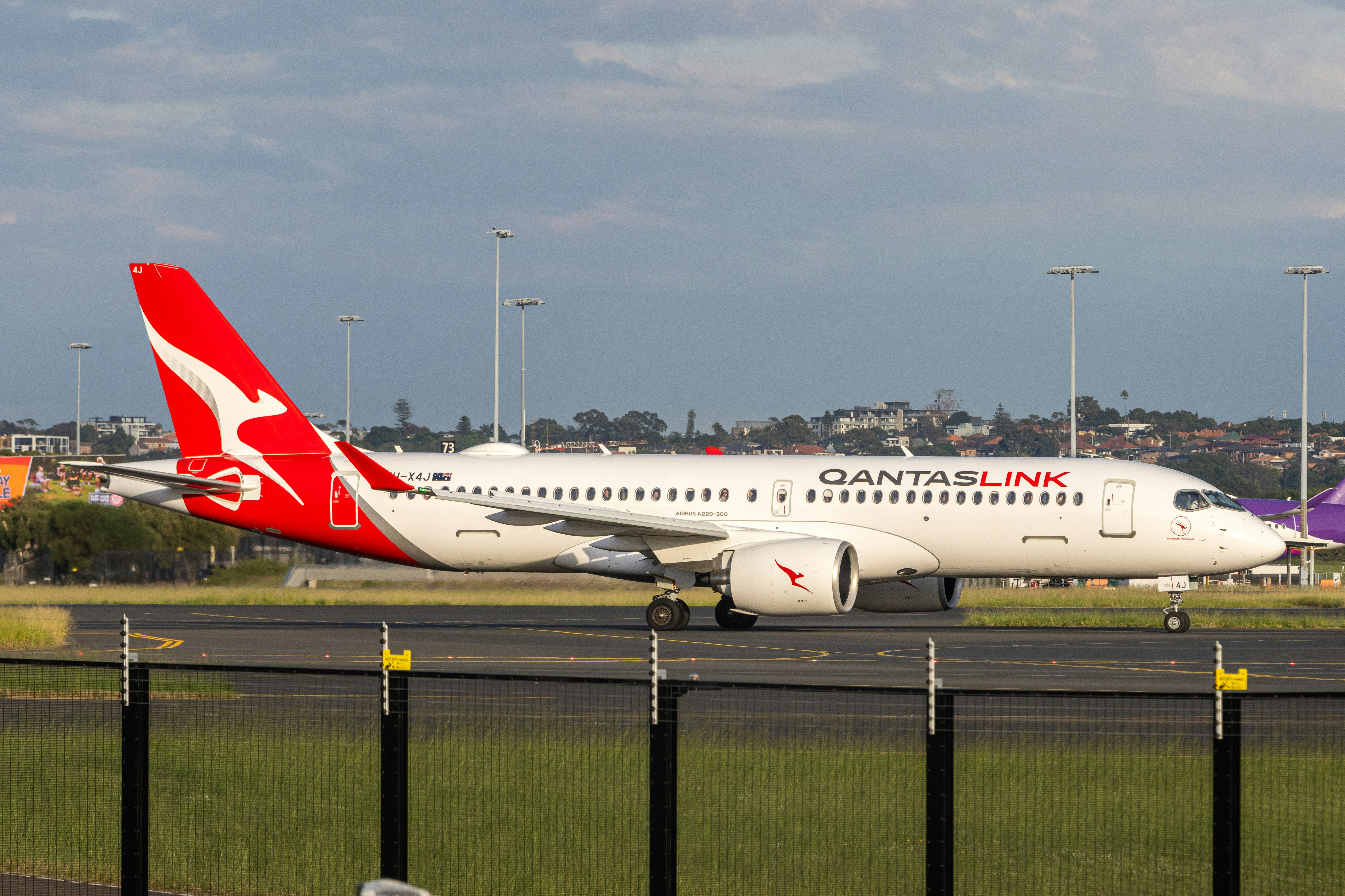 QantasLink jet at the edge of the field, tail red and white