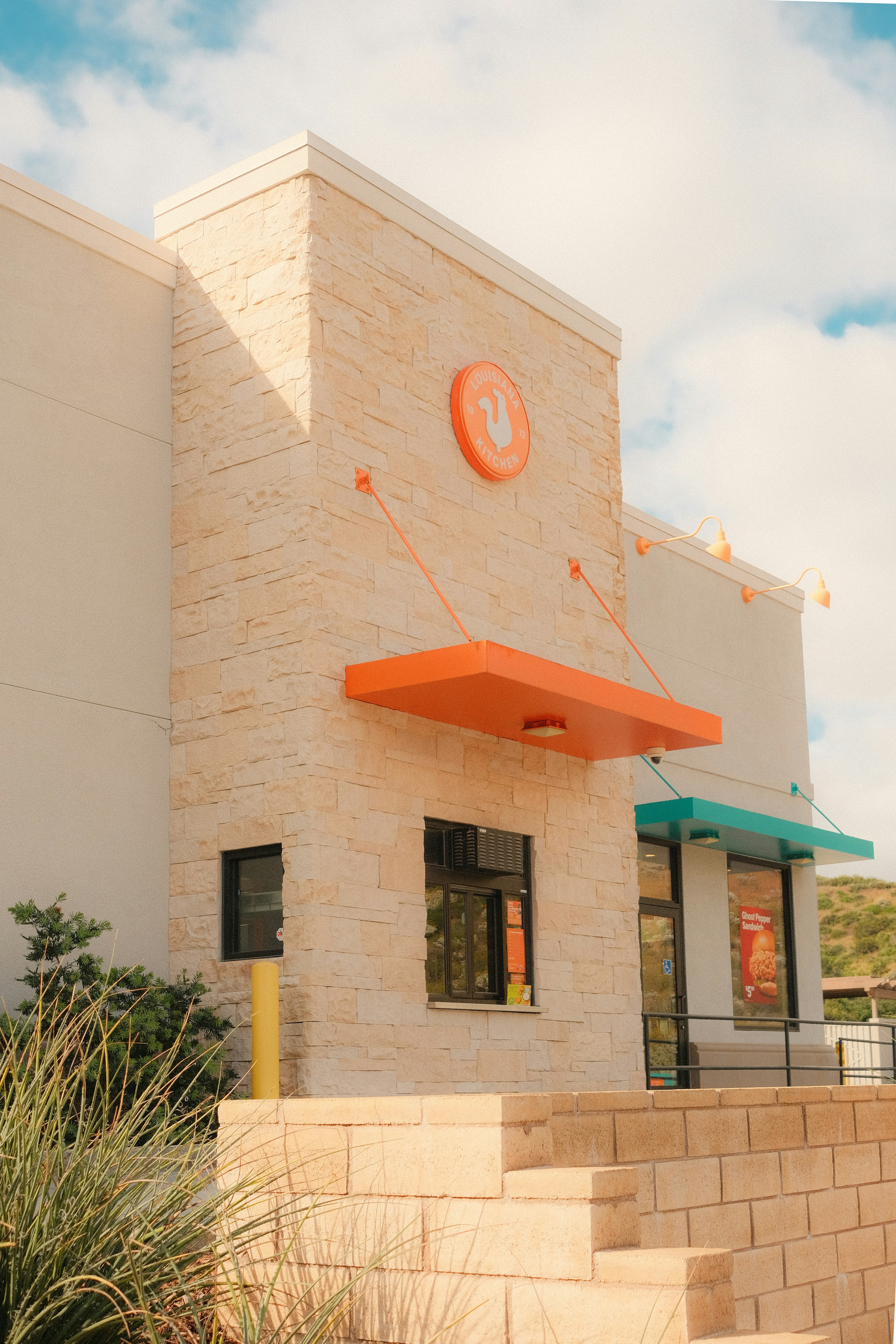 Orange canopy over a modern fast-food exterior with stone walls