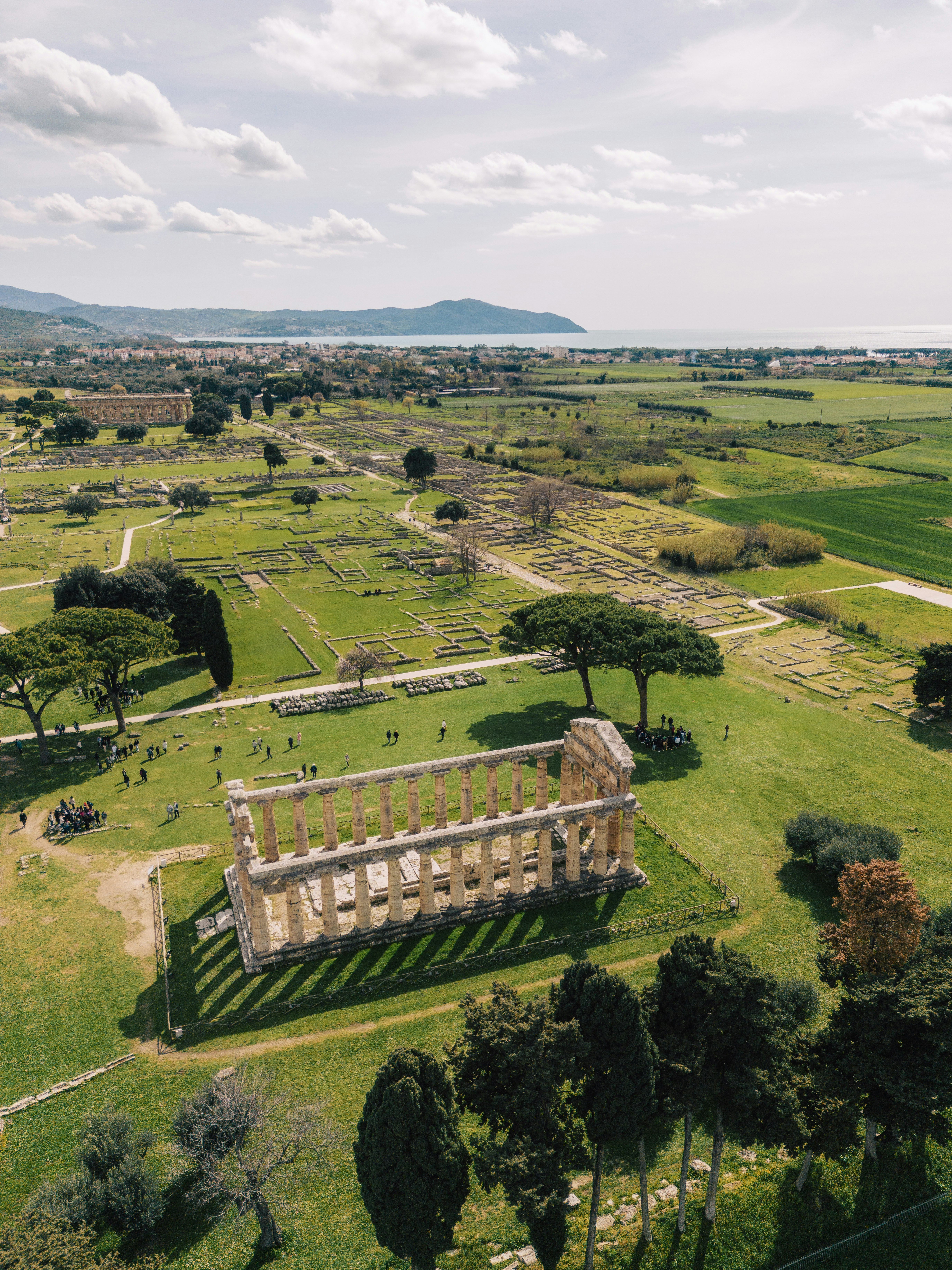 Whispering Ruins: Aerial View Over Roman Forum Relics Surrounded by Green Fields