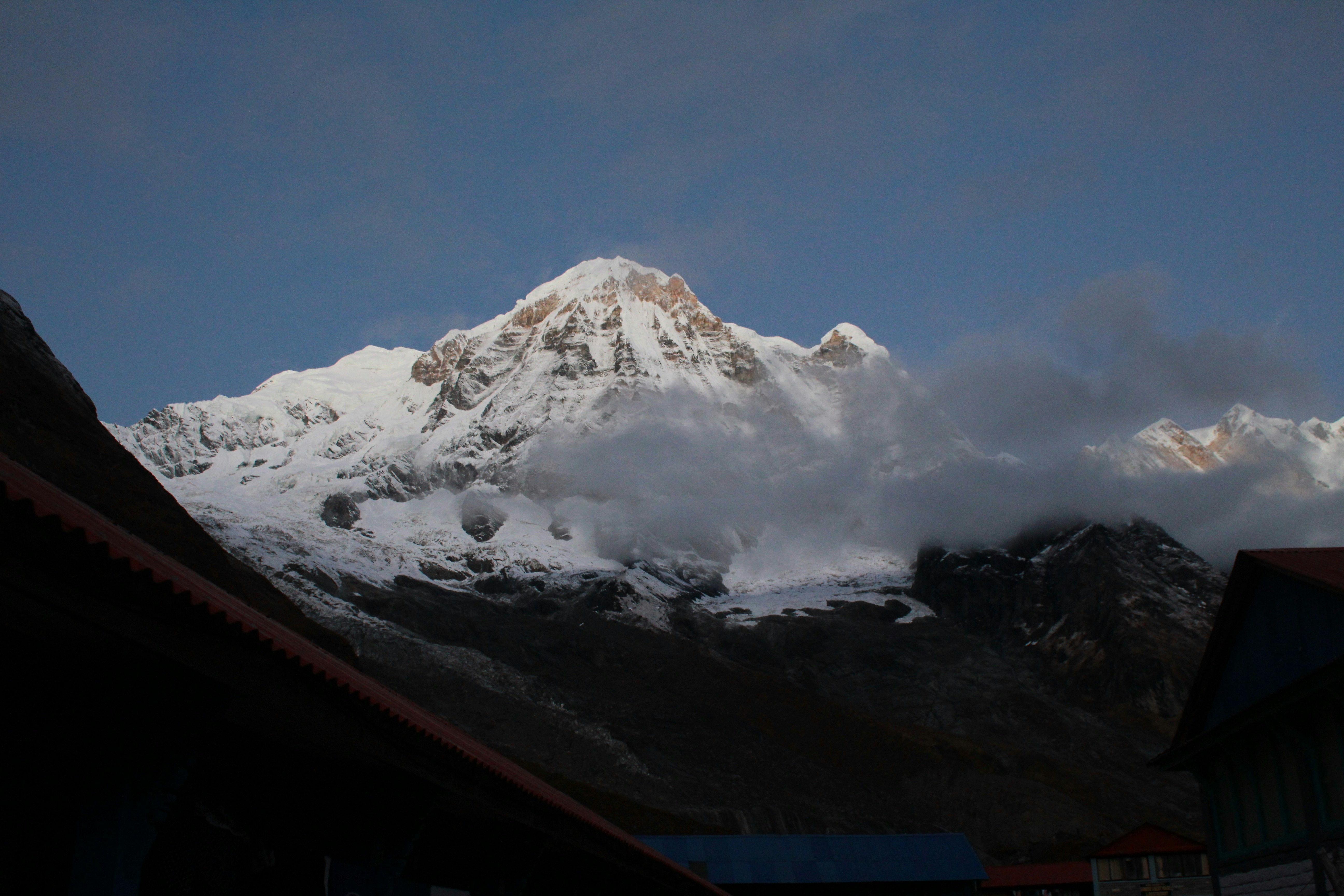 Snow-Crowned Peak Emerging Above Cloud Veil