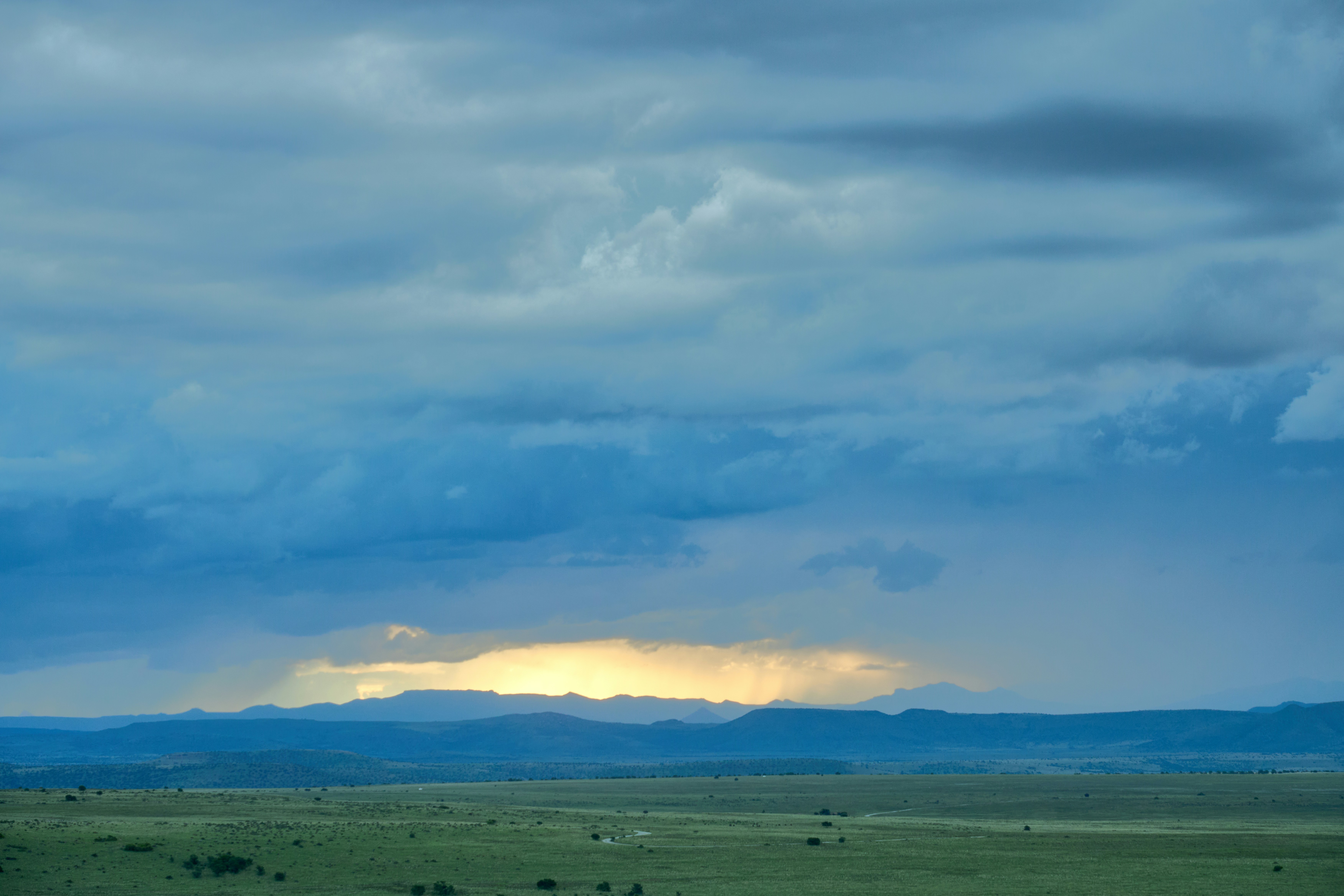 Horizon Glow Over Prairie: A Quiet Storm Bound for Sunset