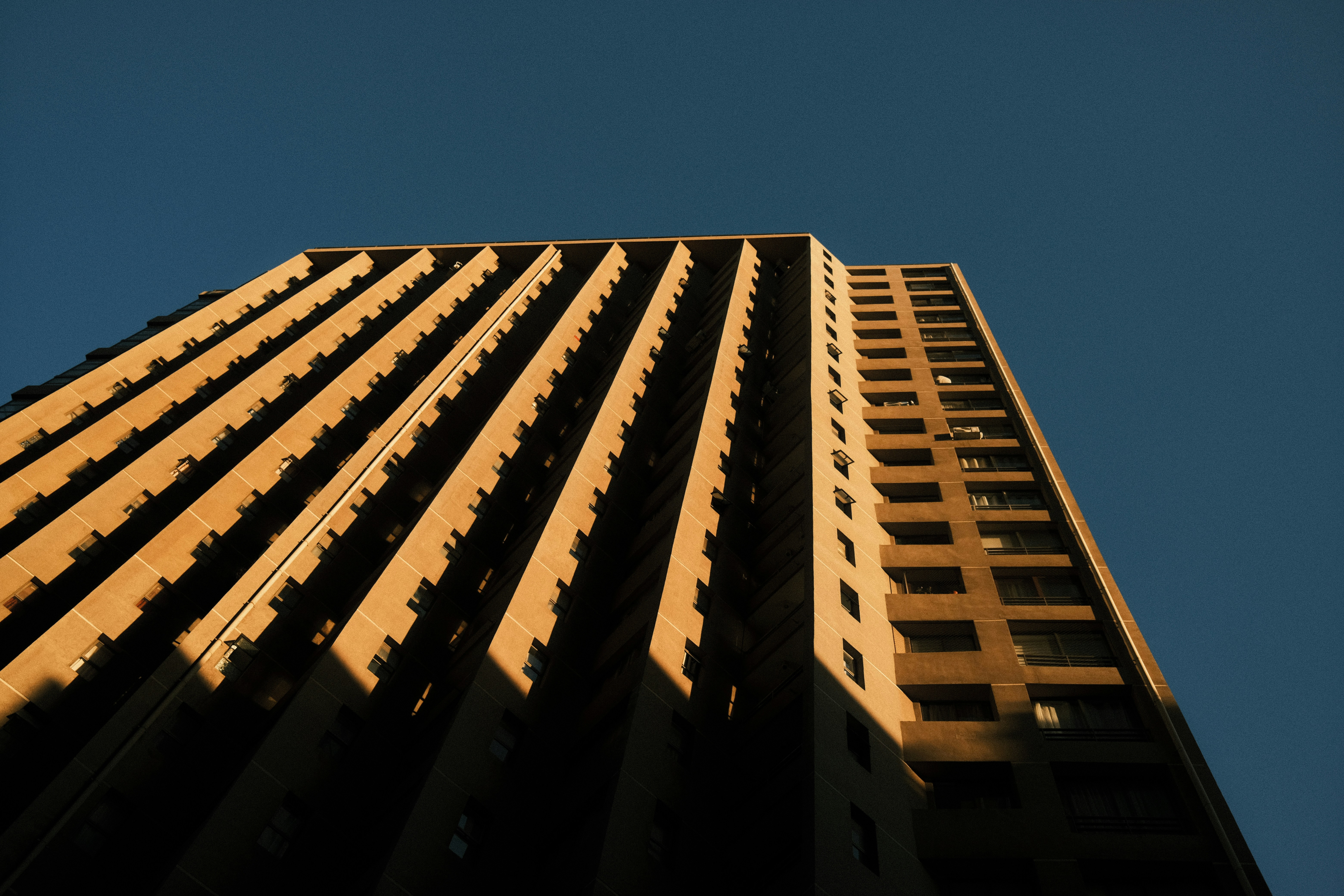 Angle of Ascendancy: A Golden Facade Rising into a Clear Sky