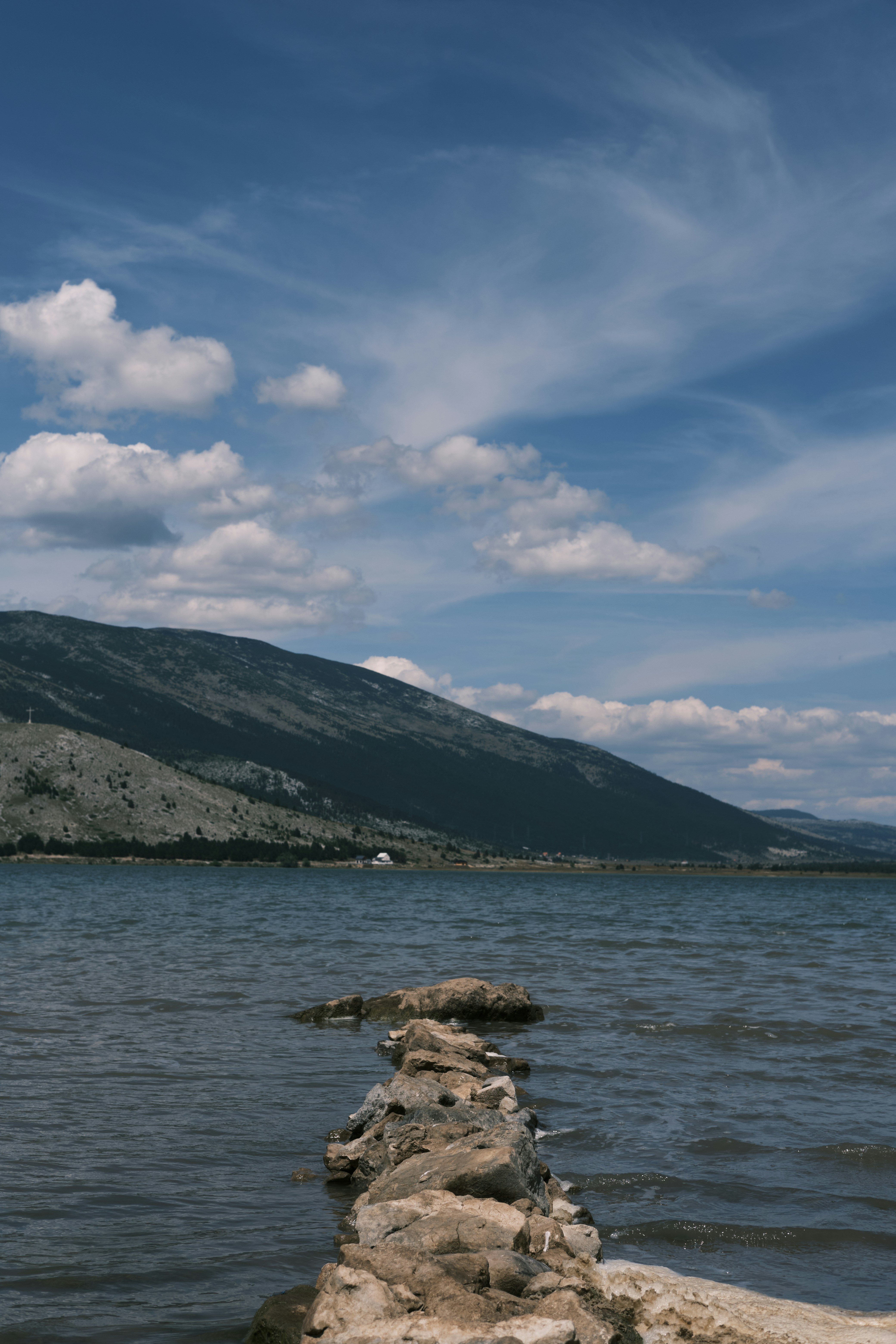 Stone Pier Reaching Toward a Quiet Lake Under Expansive Sky