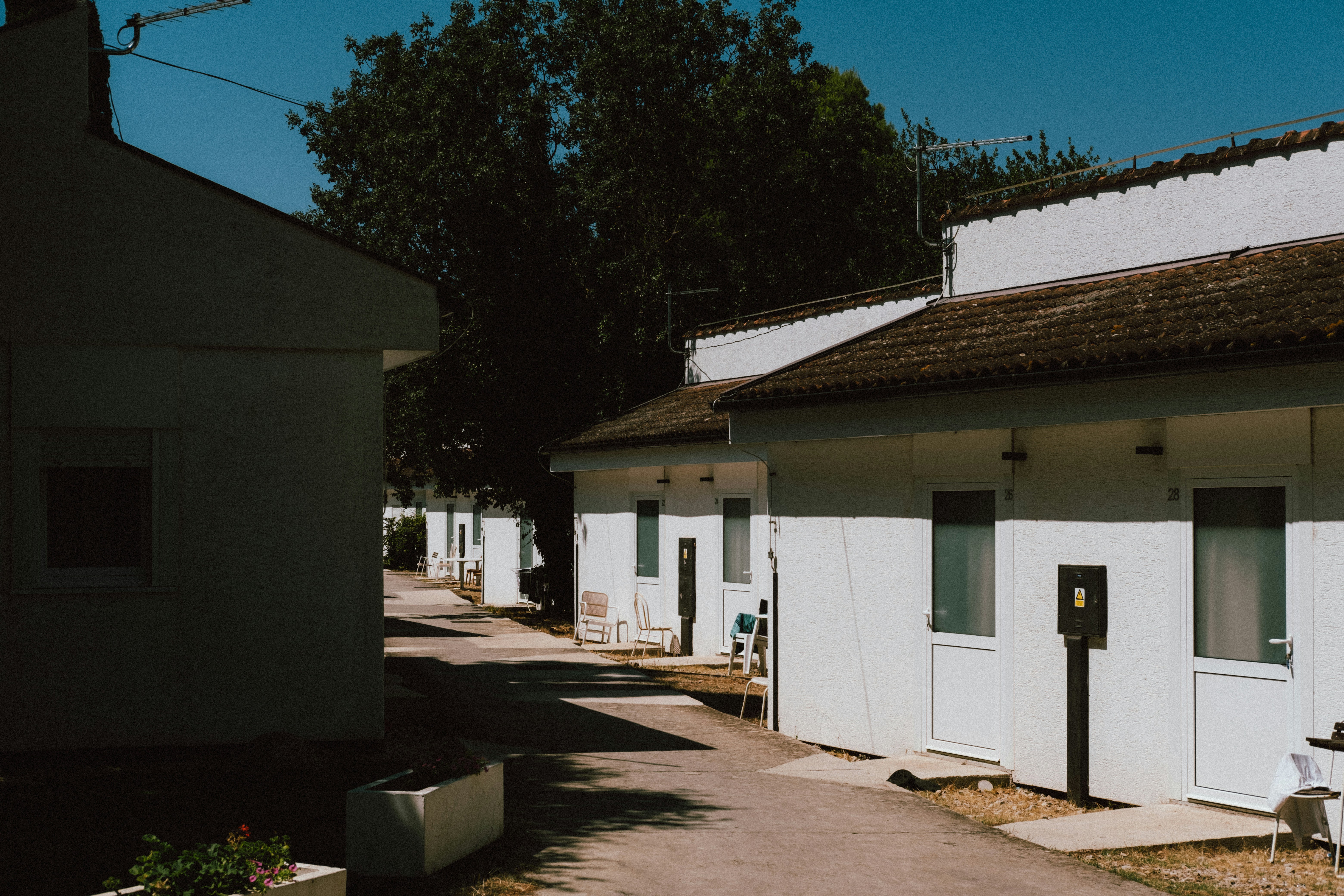 Sunlit alley of white-walled studios with a shaded path