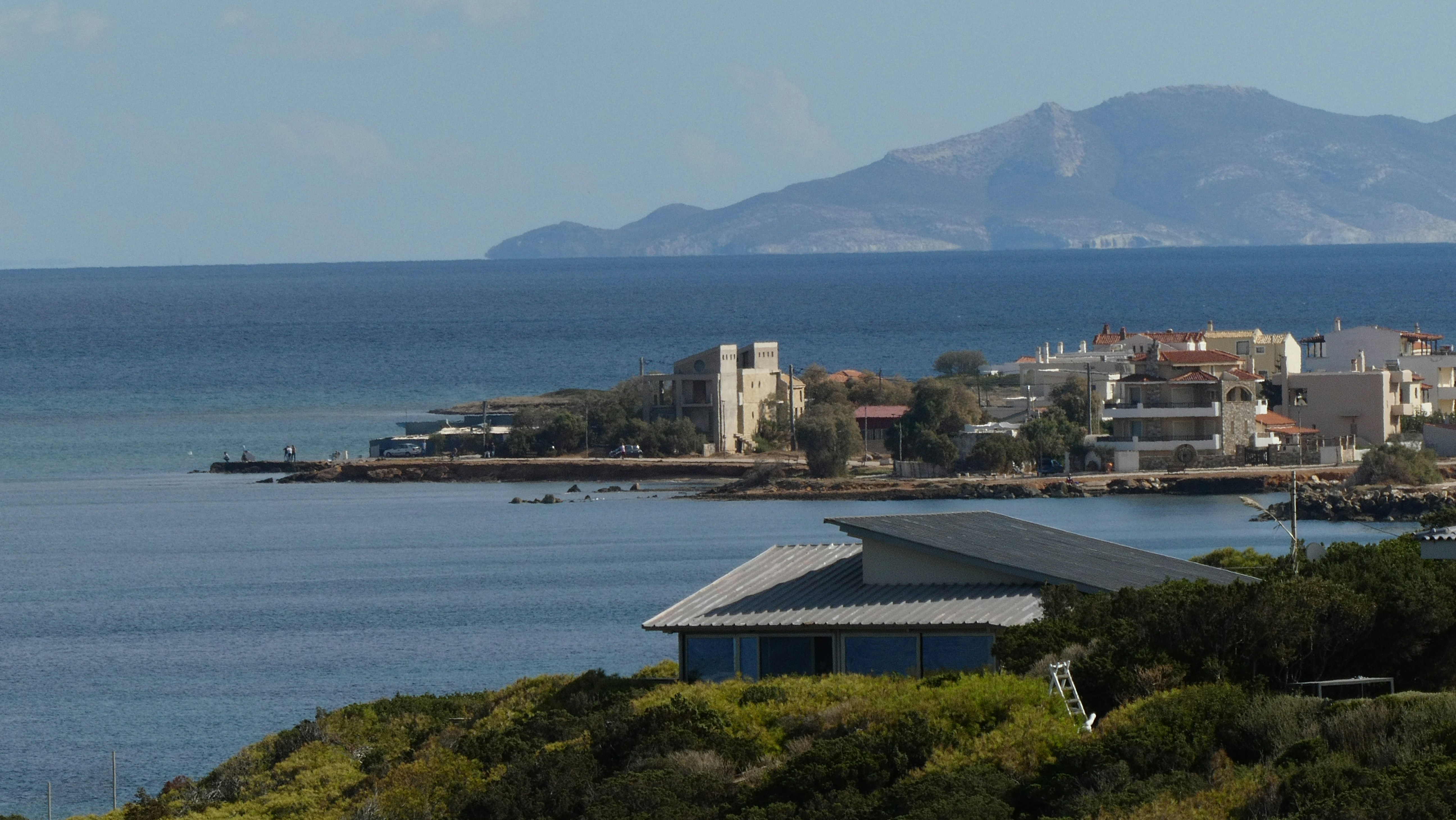 Coastal Town Silhouette: Pier, Sea, and Distant Mountains