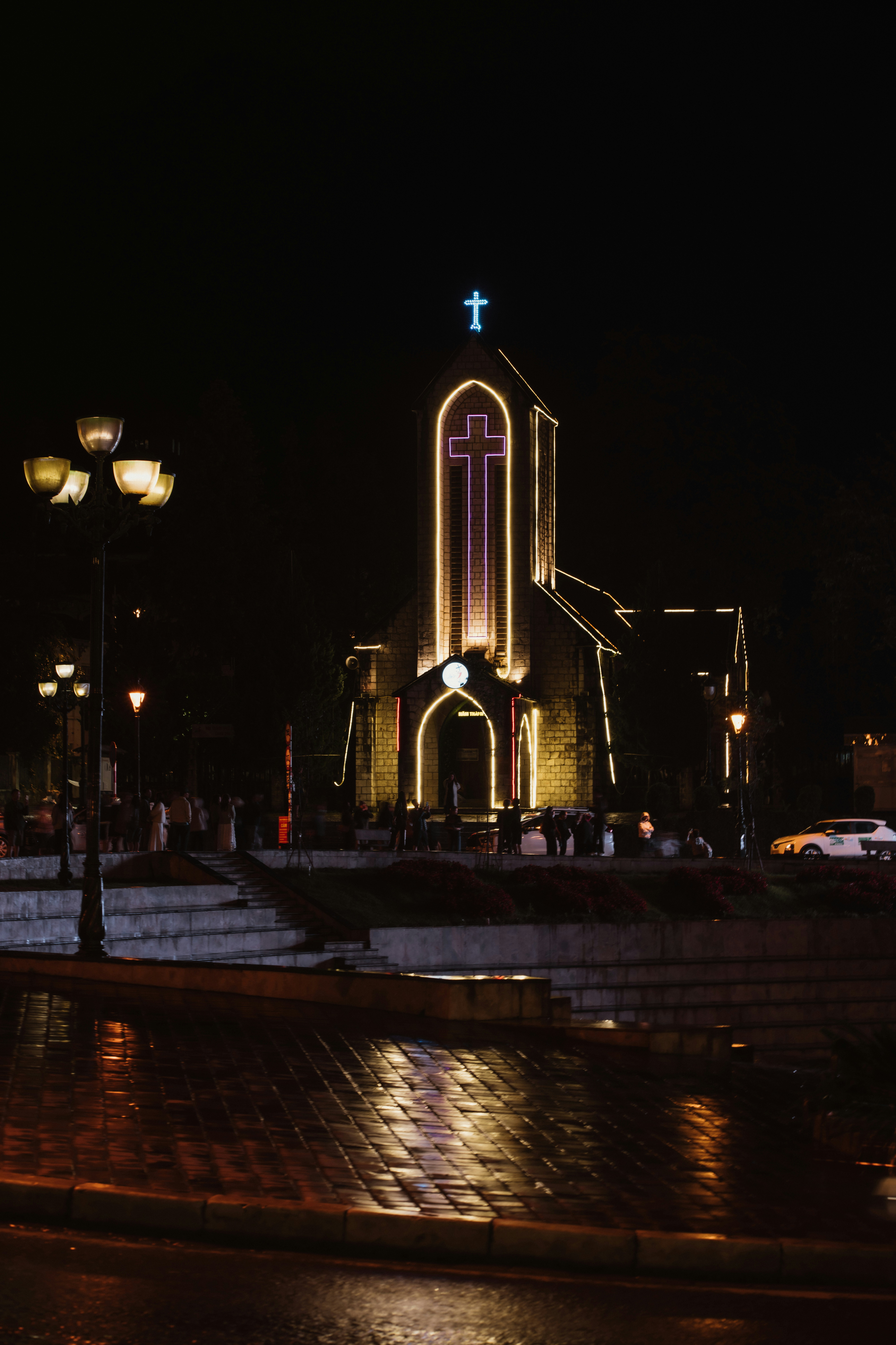 Neon-lit chapel at night by a reflective quay