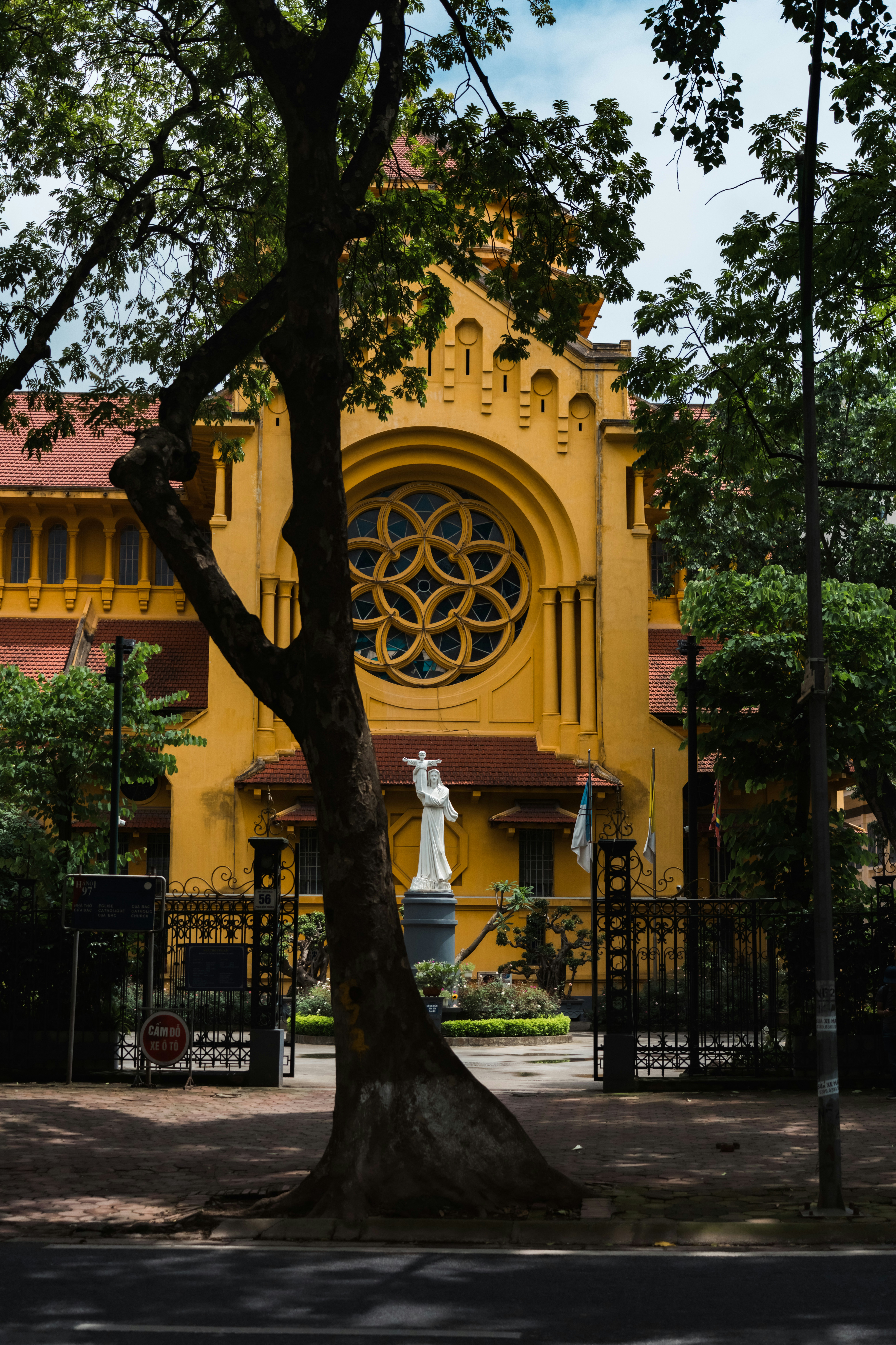 Yellow church facade framing a statuesque centerpiece through a tree