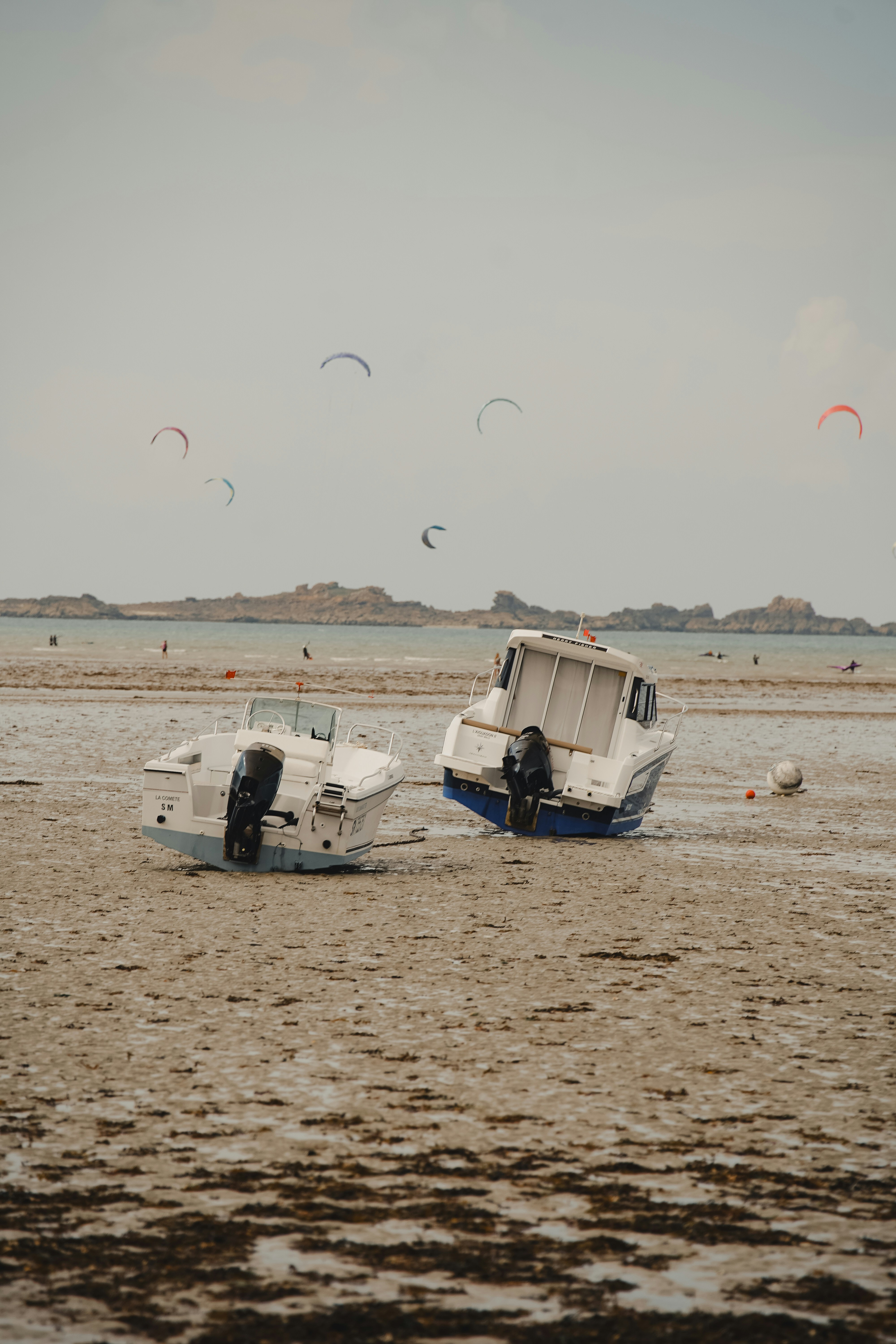 Harbor Boats Rest on the Tidal Plain as Kites Dot the Sky
