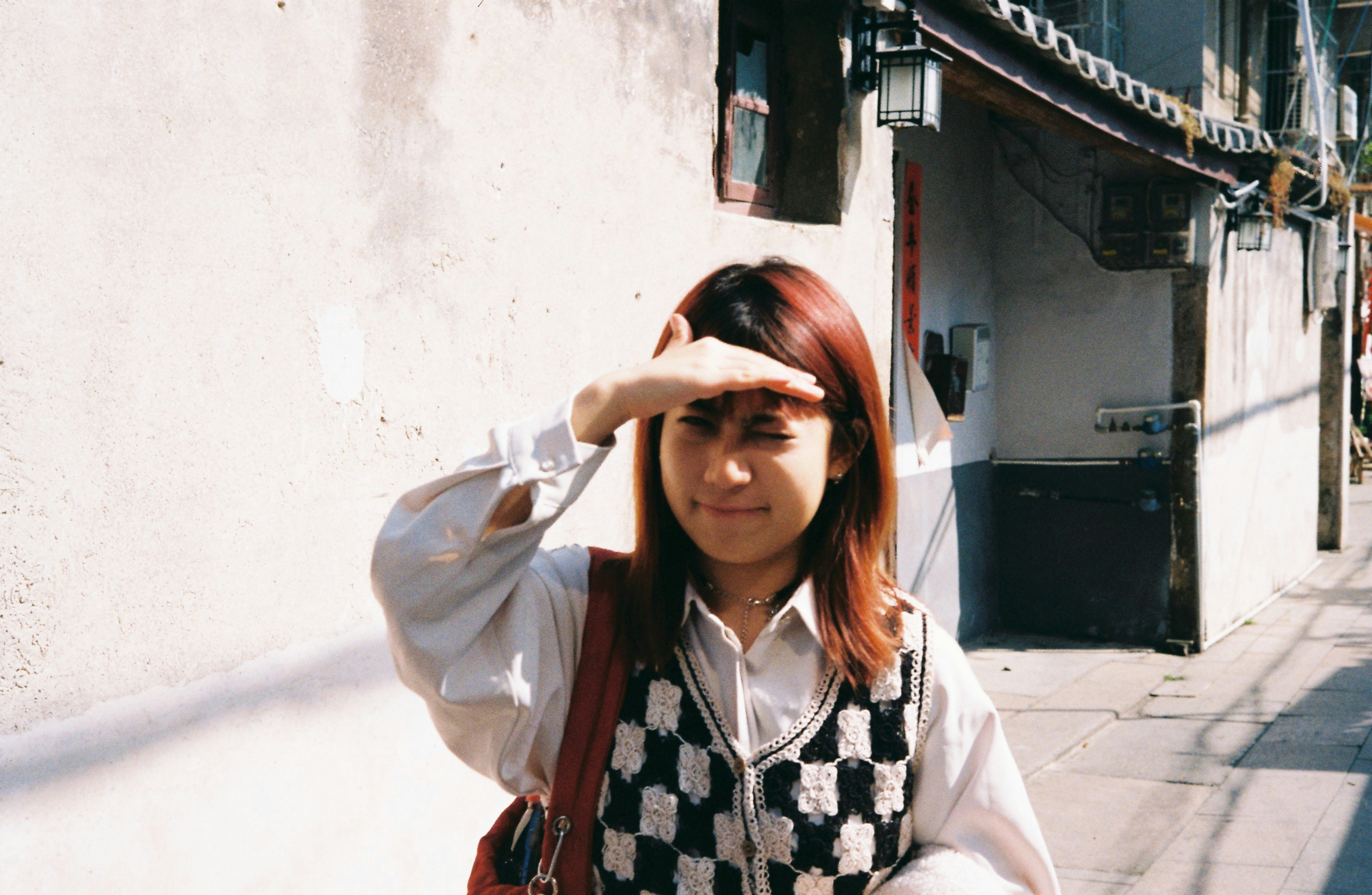 Sunlit Street Portrait: A Quiet Moment Shielded by a Hand