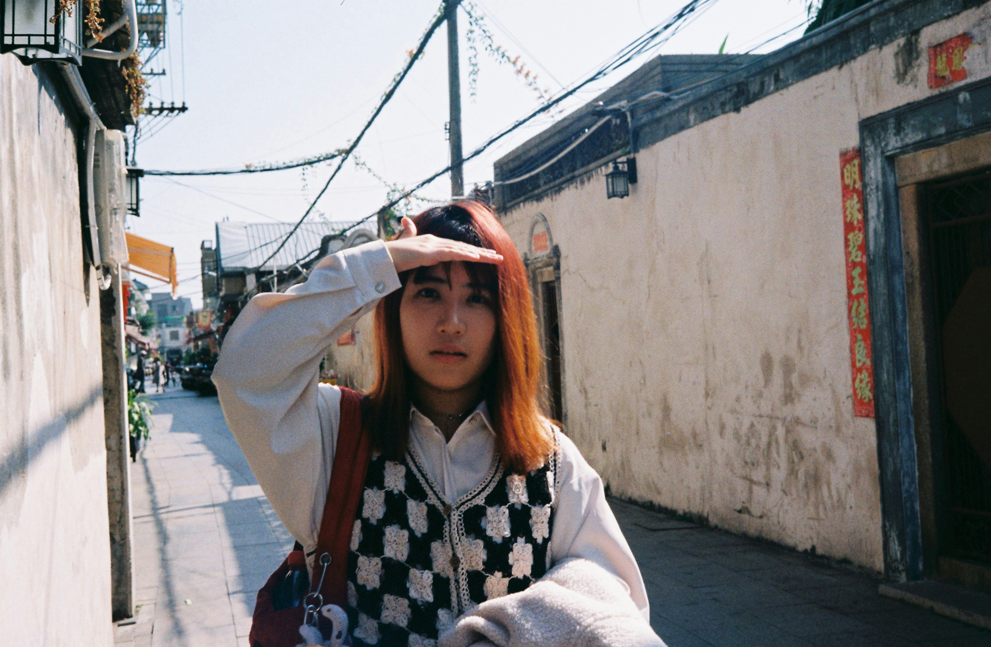 Sunlit Street Portrait: Shielding Eyes in a Quiet Alley