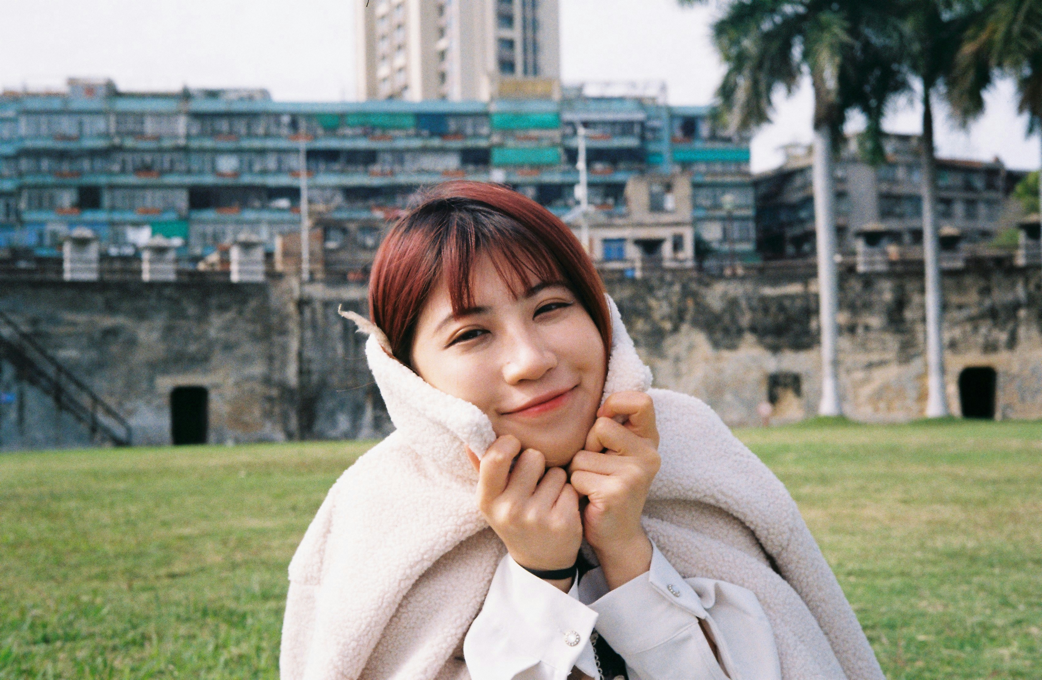 Warm Smile in the Park: A Cozy Portrait beneath City Towers
