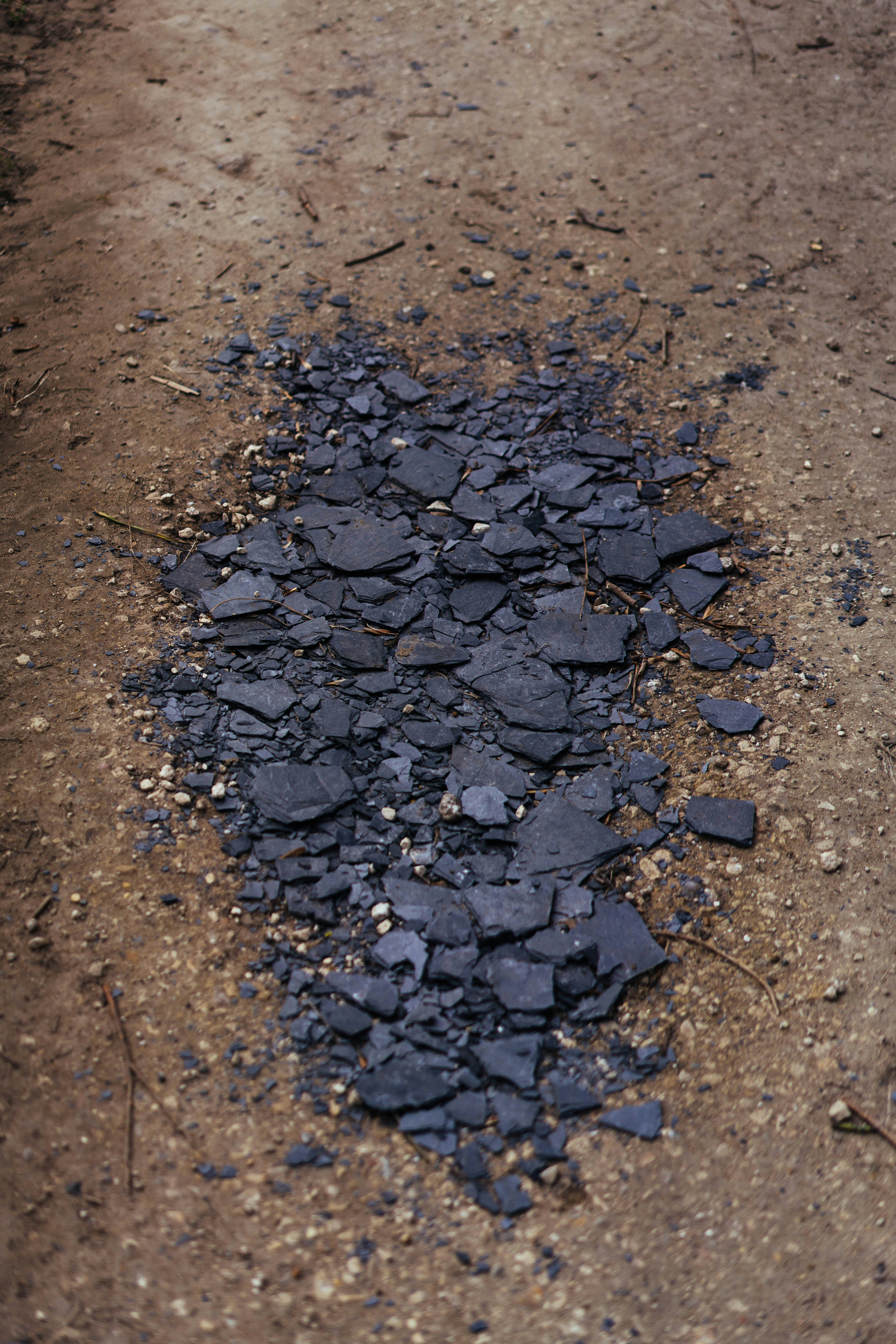 Chipped slate trail of dark fragments on earthen path