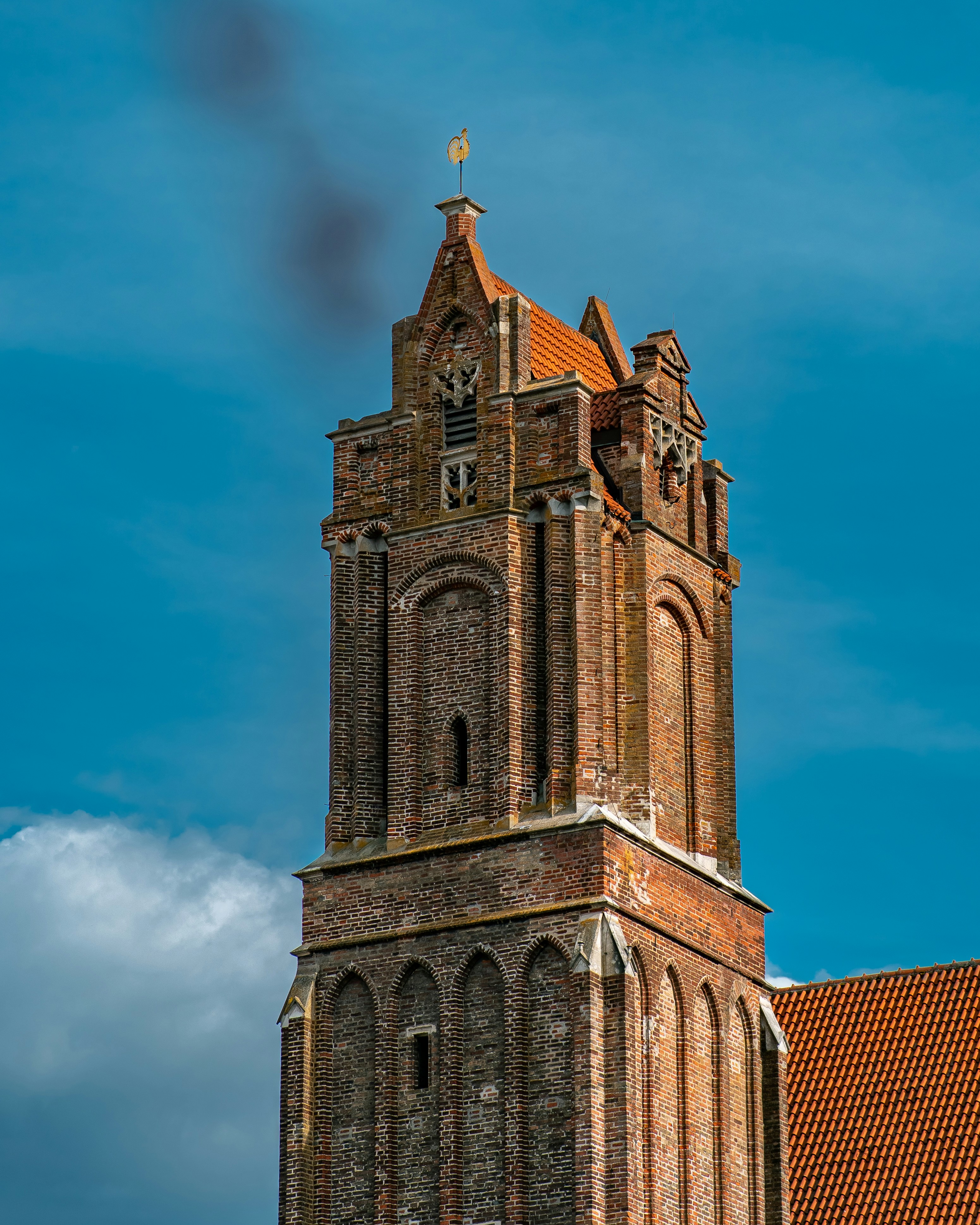 Brick Tower Crowned by a Weather Vane Against a Clear Sky