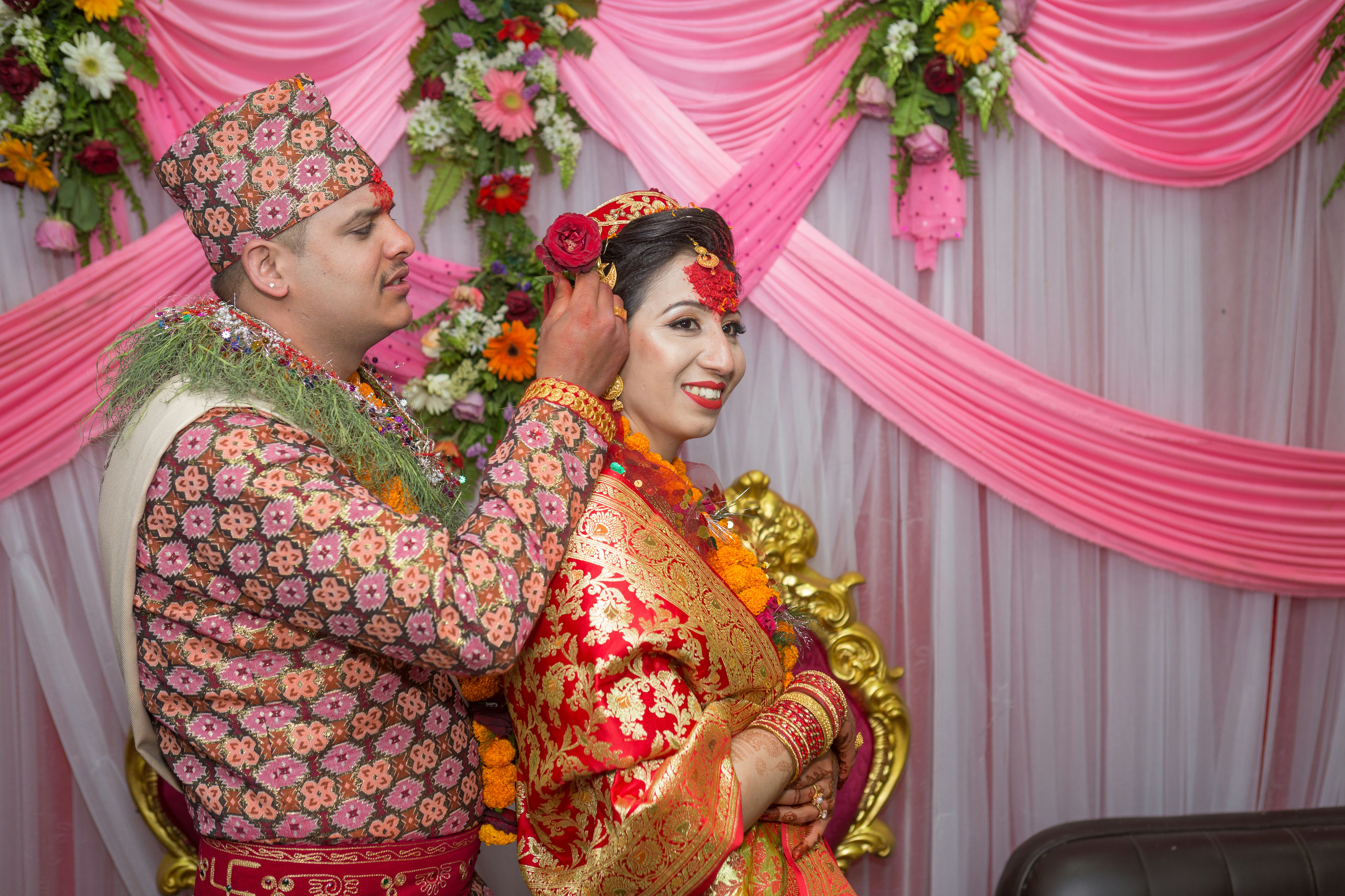 Bride Seated as Groom Adjusts Her Hair in a Colorful Traditional Ceremony