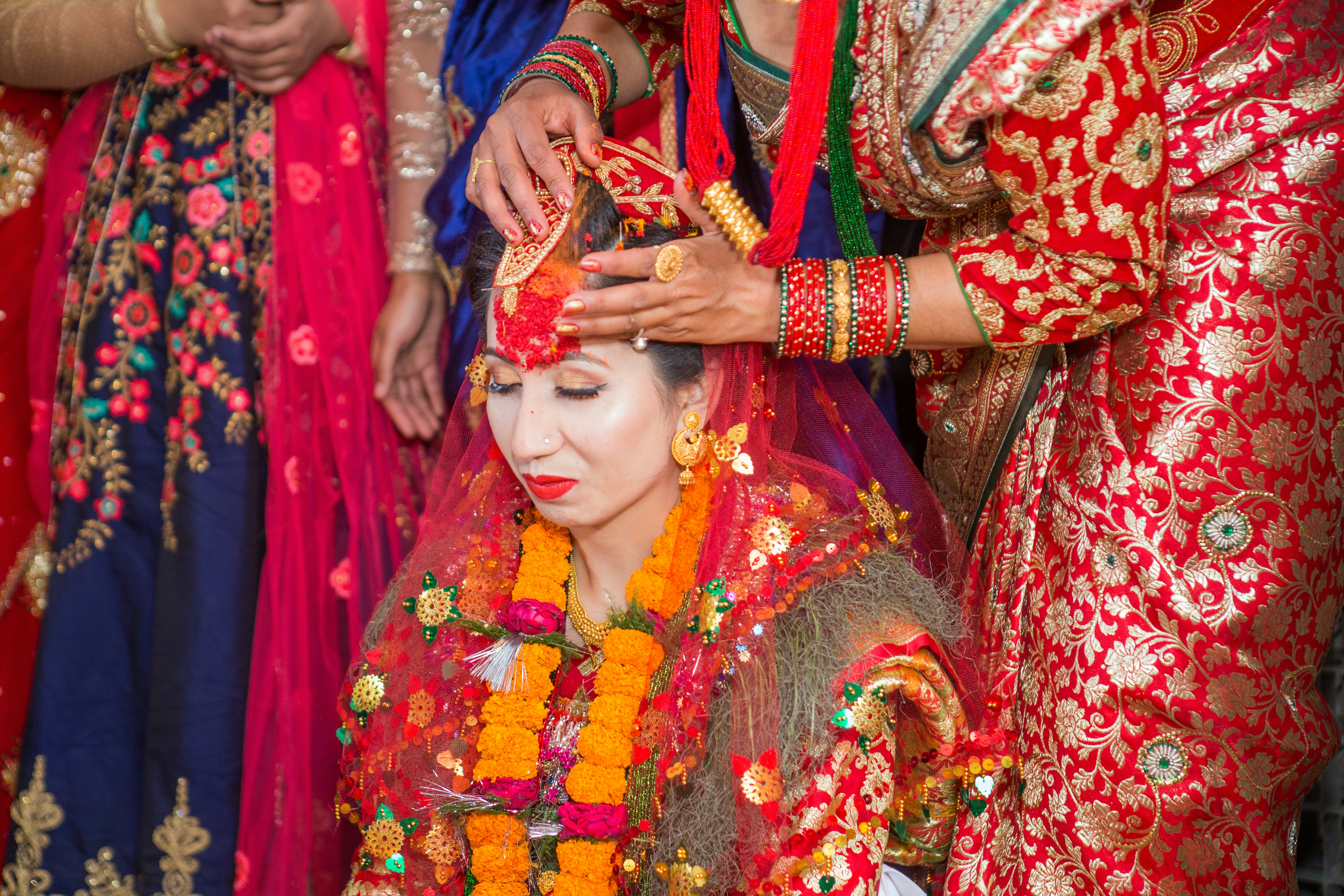 Garlanded Bride Under Blessing, Quiet Amid Vivid Ceremony