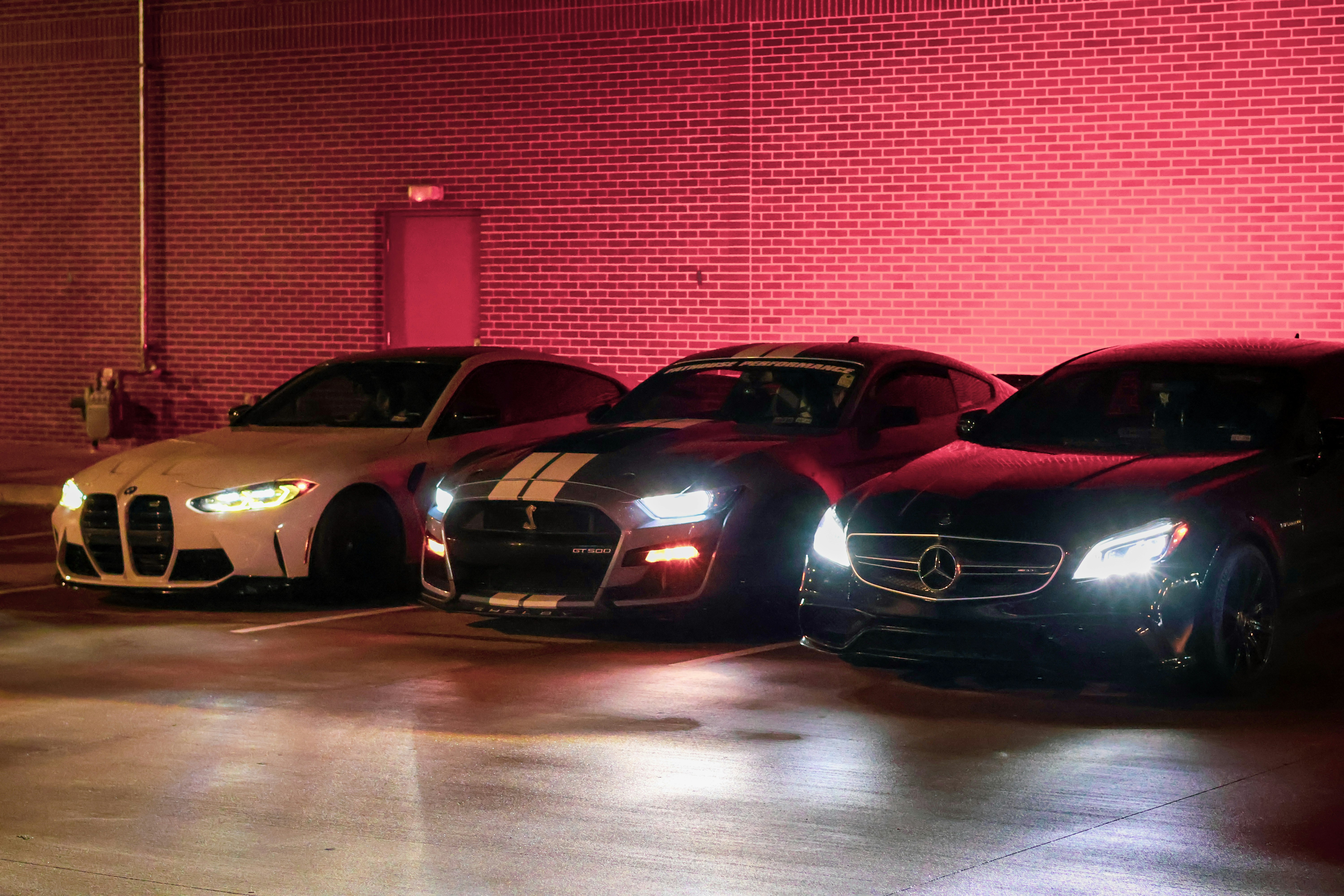 Midnight Row: Three Luxury Cars Bathed in Neon Beam