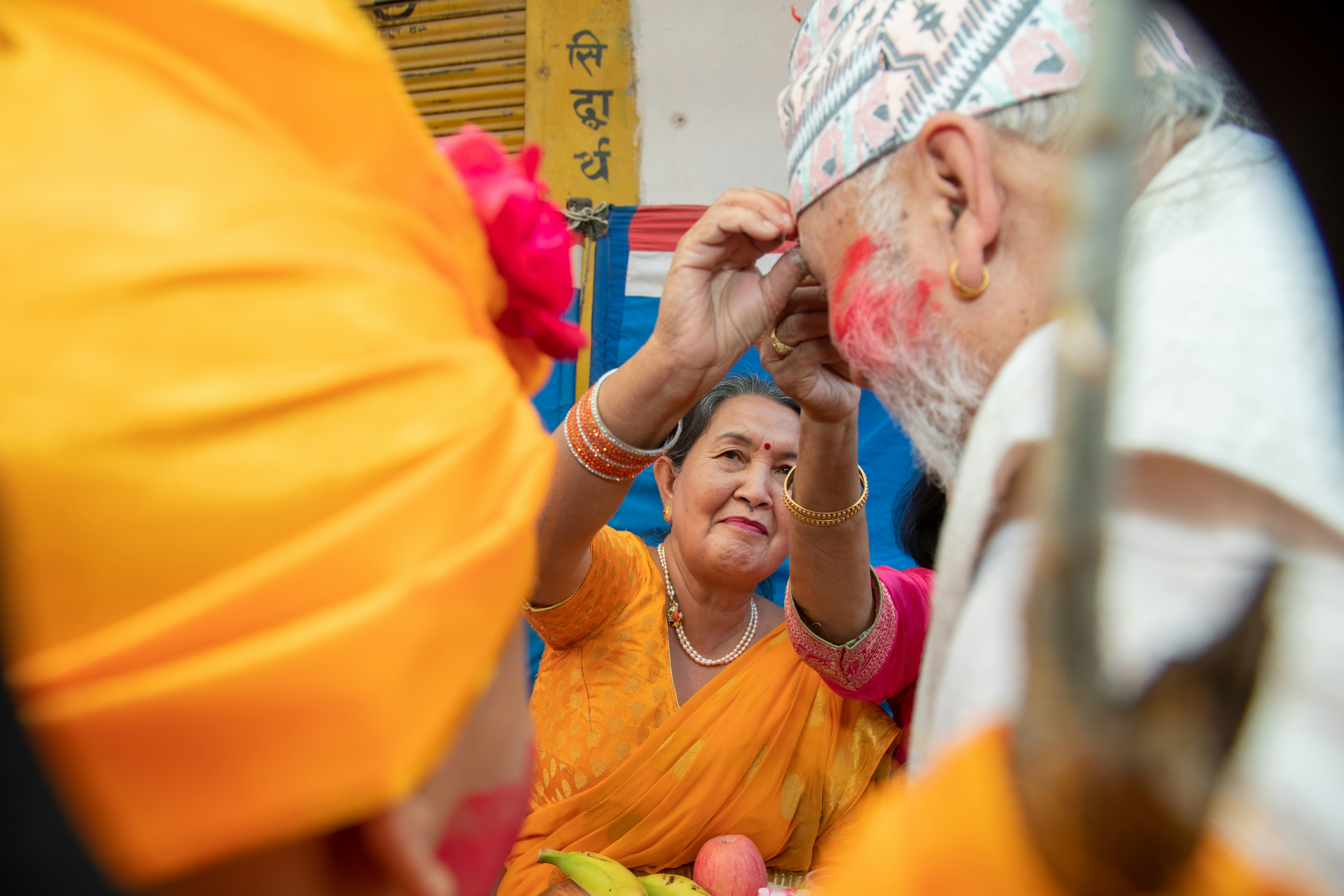 Ritual Moment: A Celebrant Adjusts the Forehead Mark Amid a Colorful Gathering