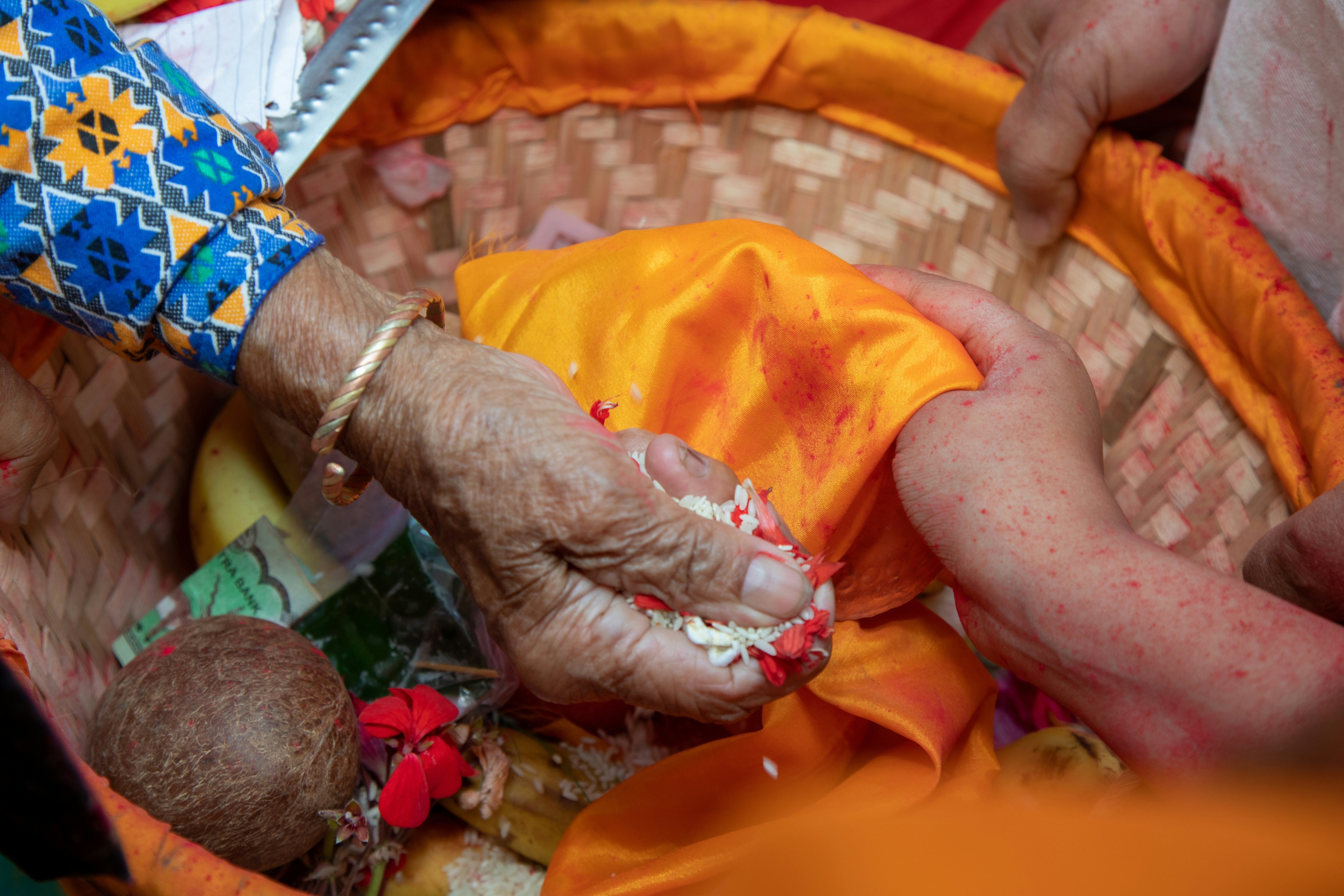 Hands of Tradition: A Sacred Gesture in a Bright Orange Cloth