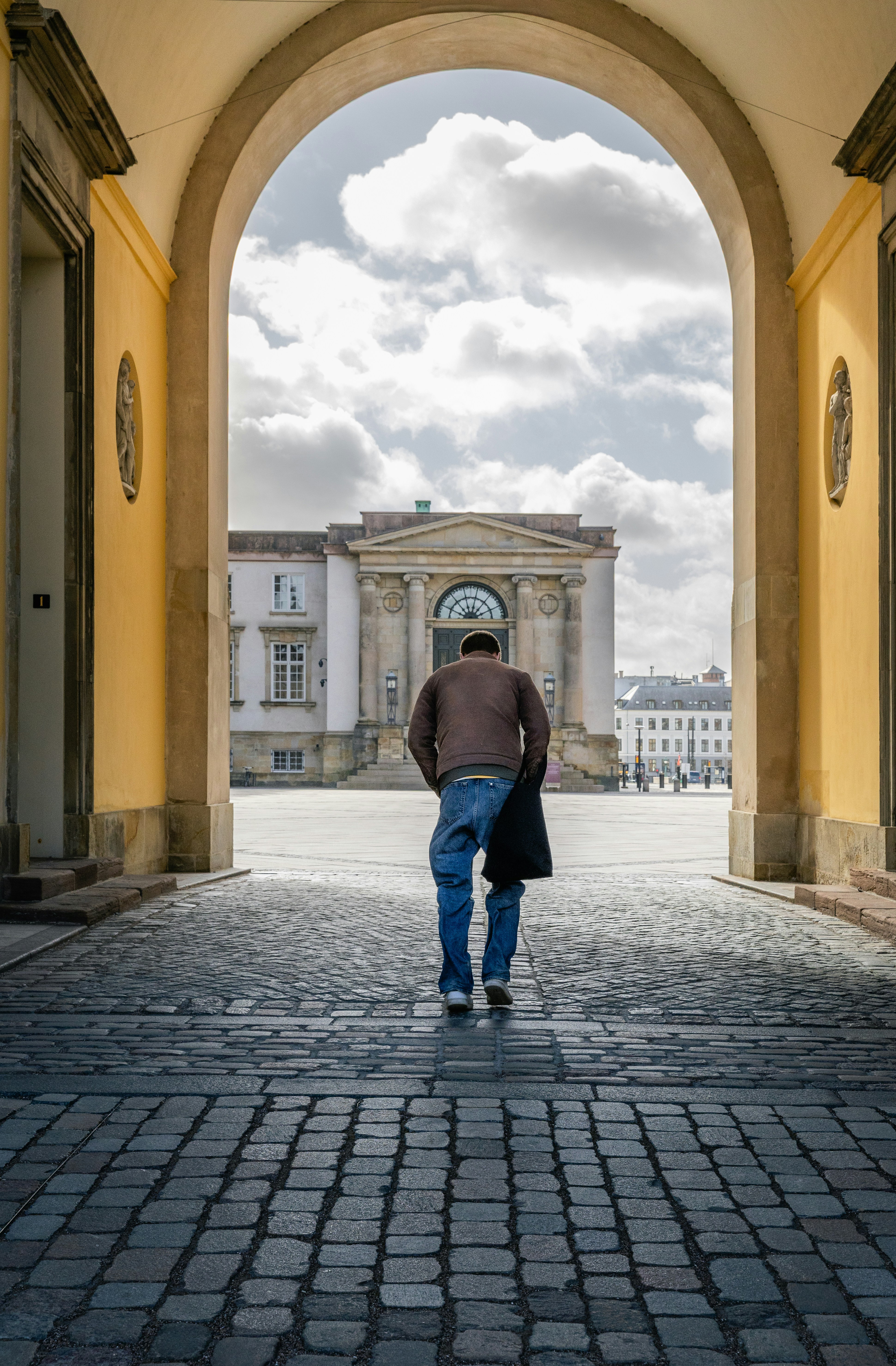 Runner in the Arch: A Street-arcade Crossing Framed by Yellow Walls