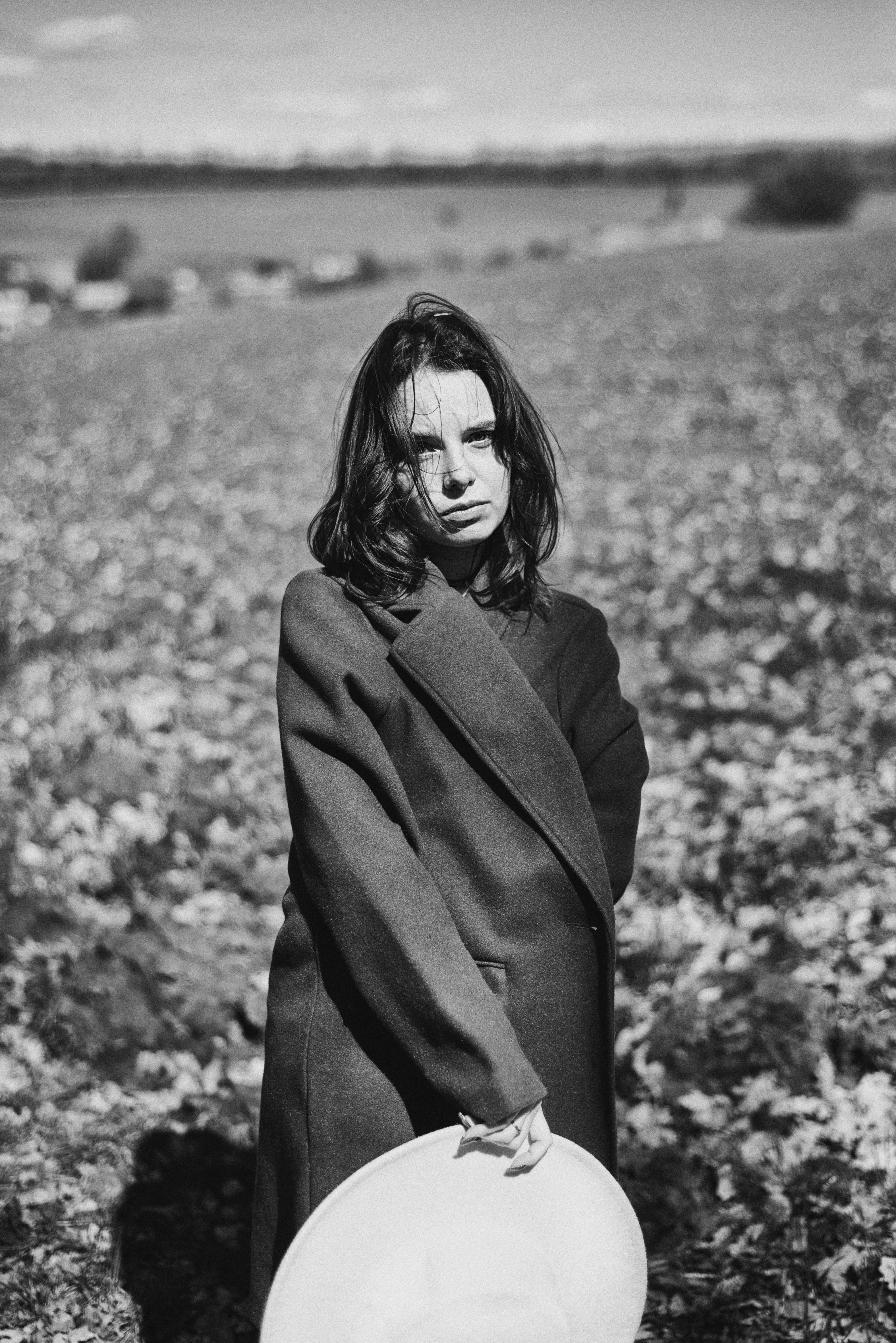 Portrait in Winter Field: A Woman with Coat and Hat in Soft Sunlight