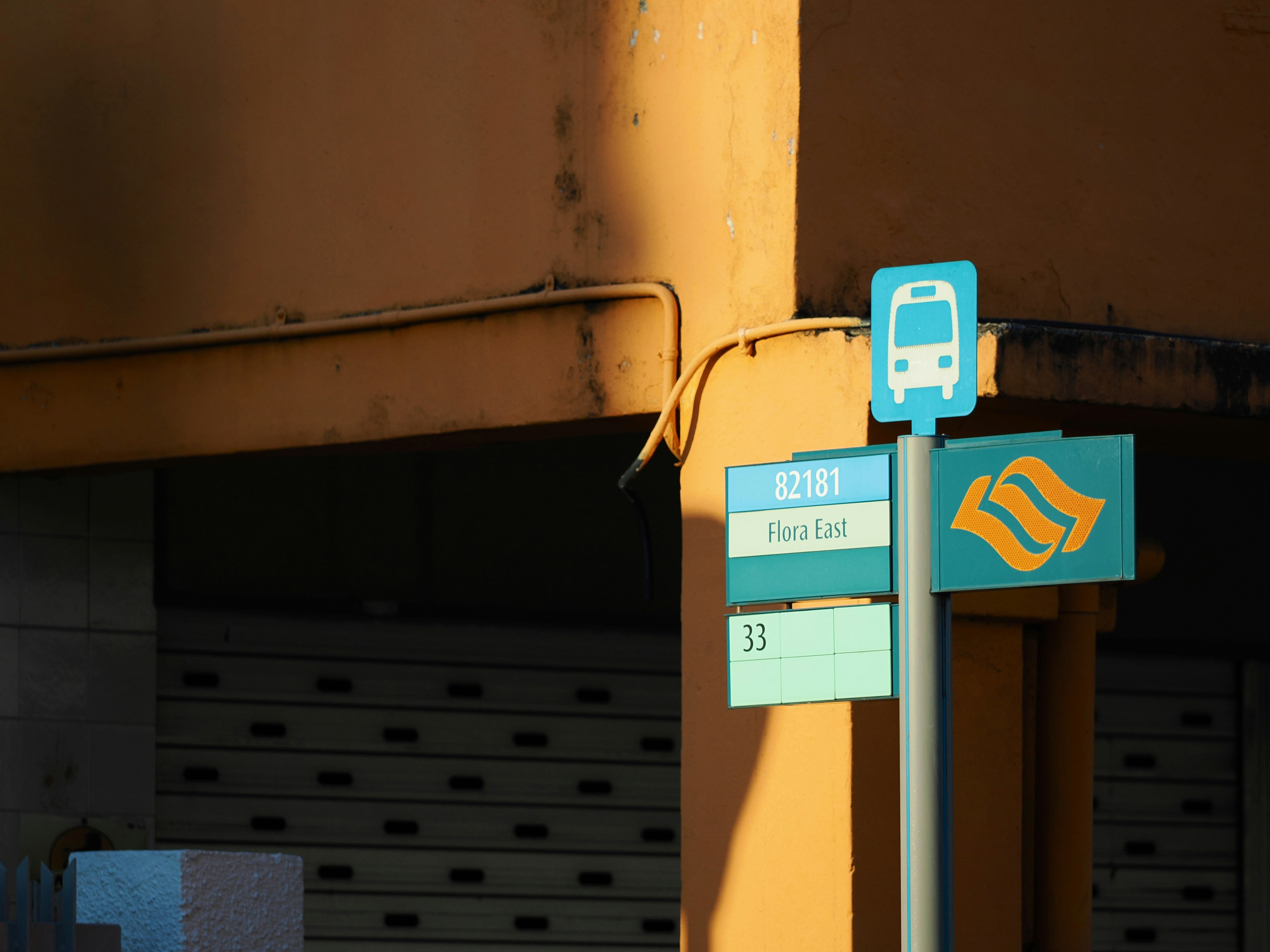 Sunlit Bus Stop Sign Painted in Warm Orange