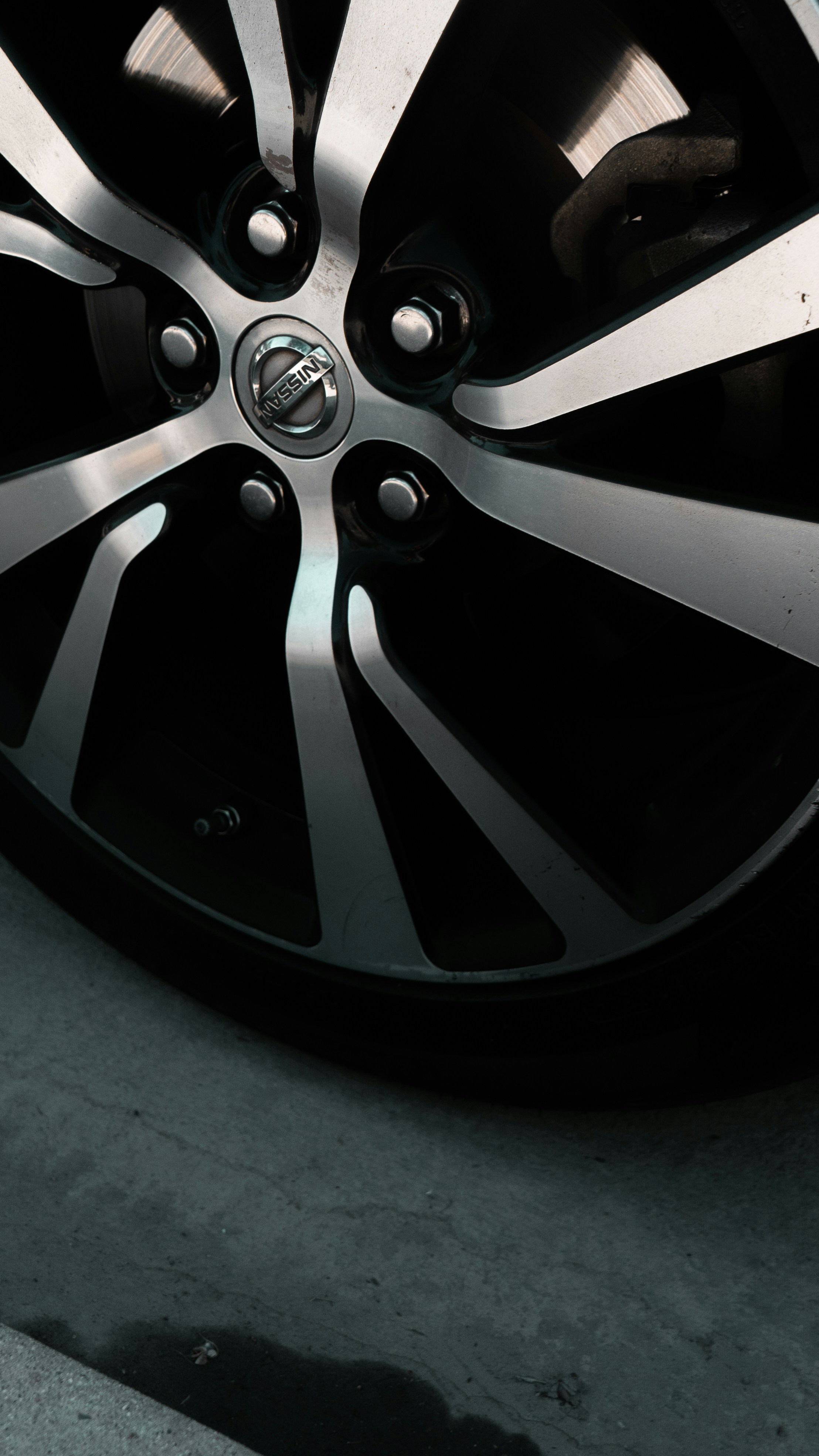 Close-up of a Nissan alloy wheel: metallic spokes and central badge