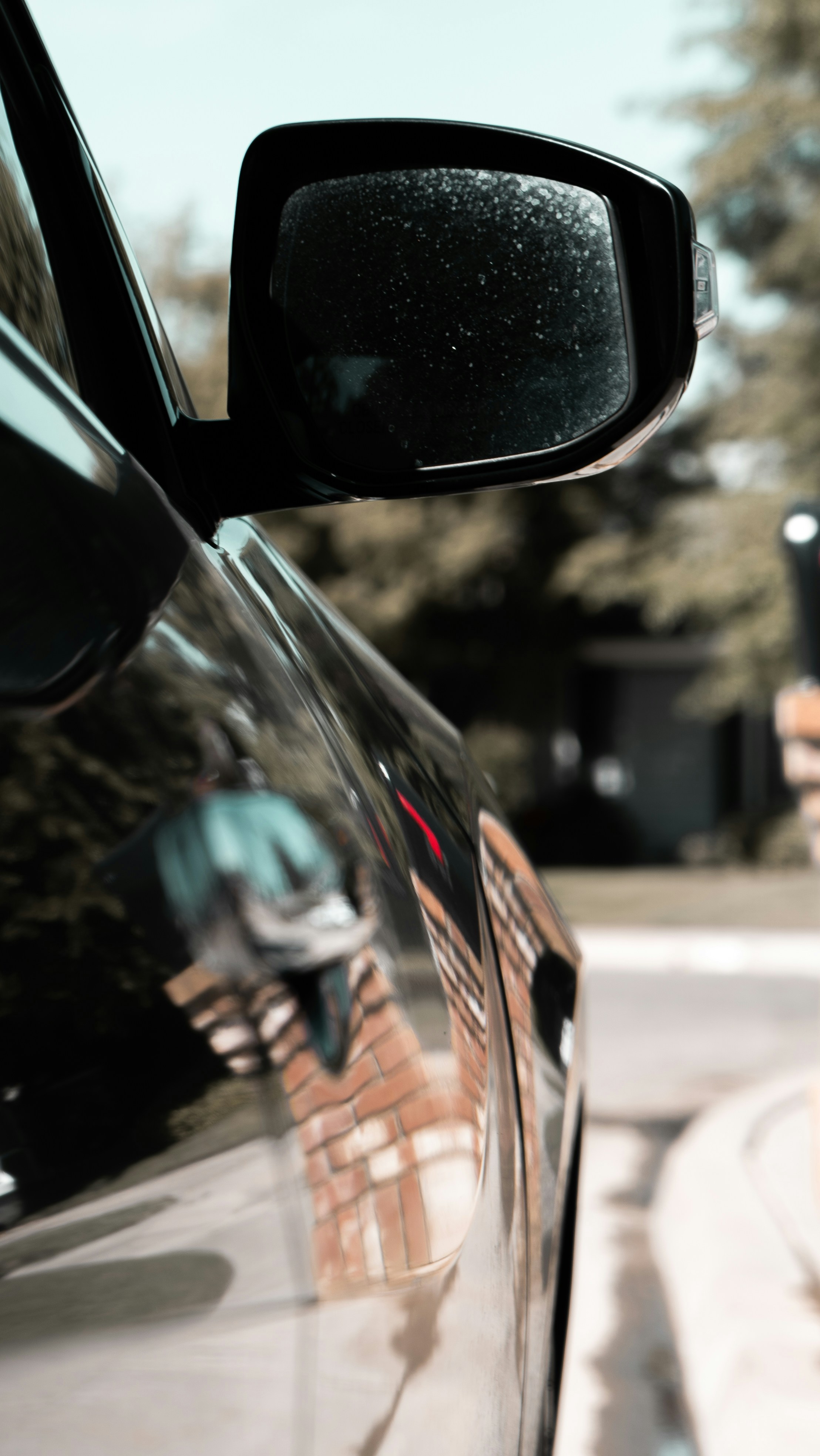 Close-up of a car side-view mirror with a blurred urban background