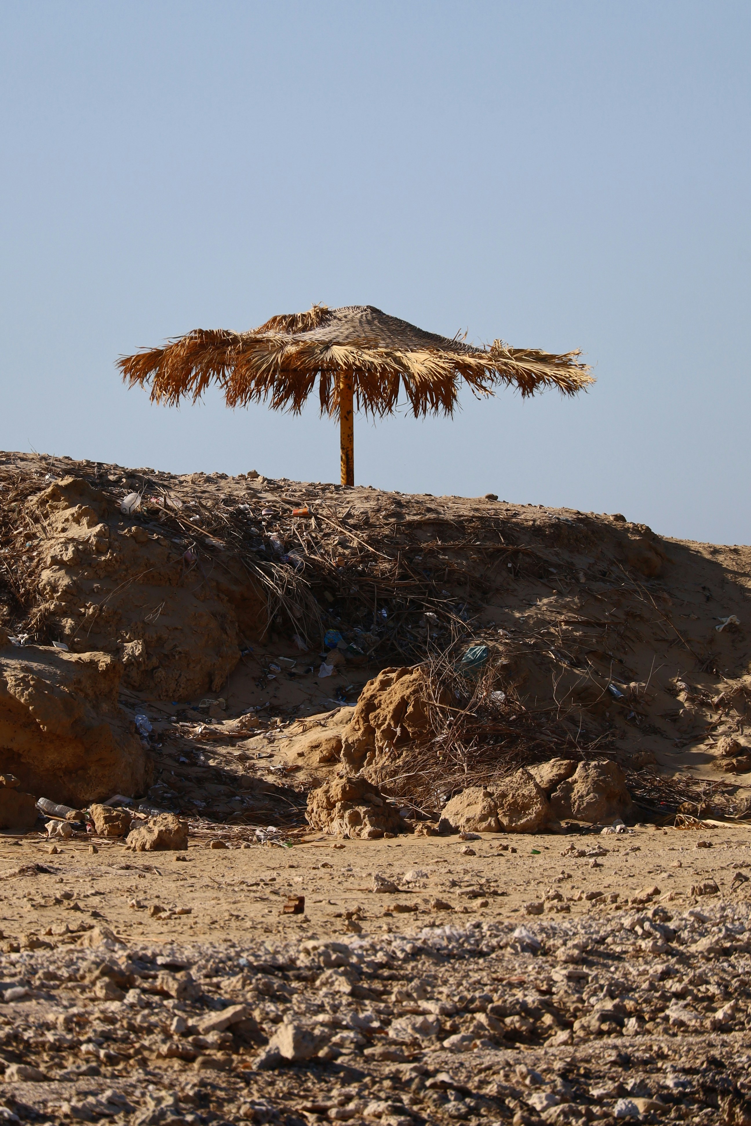 Desert canopy: lone thatched parasol perched on eroded ridge