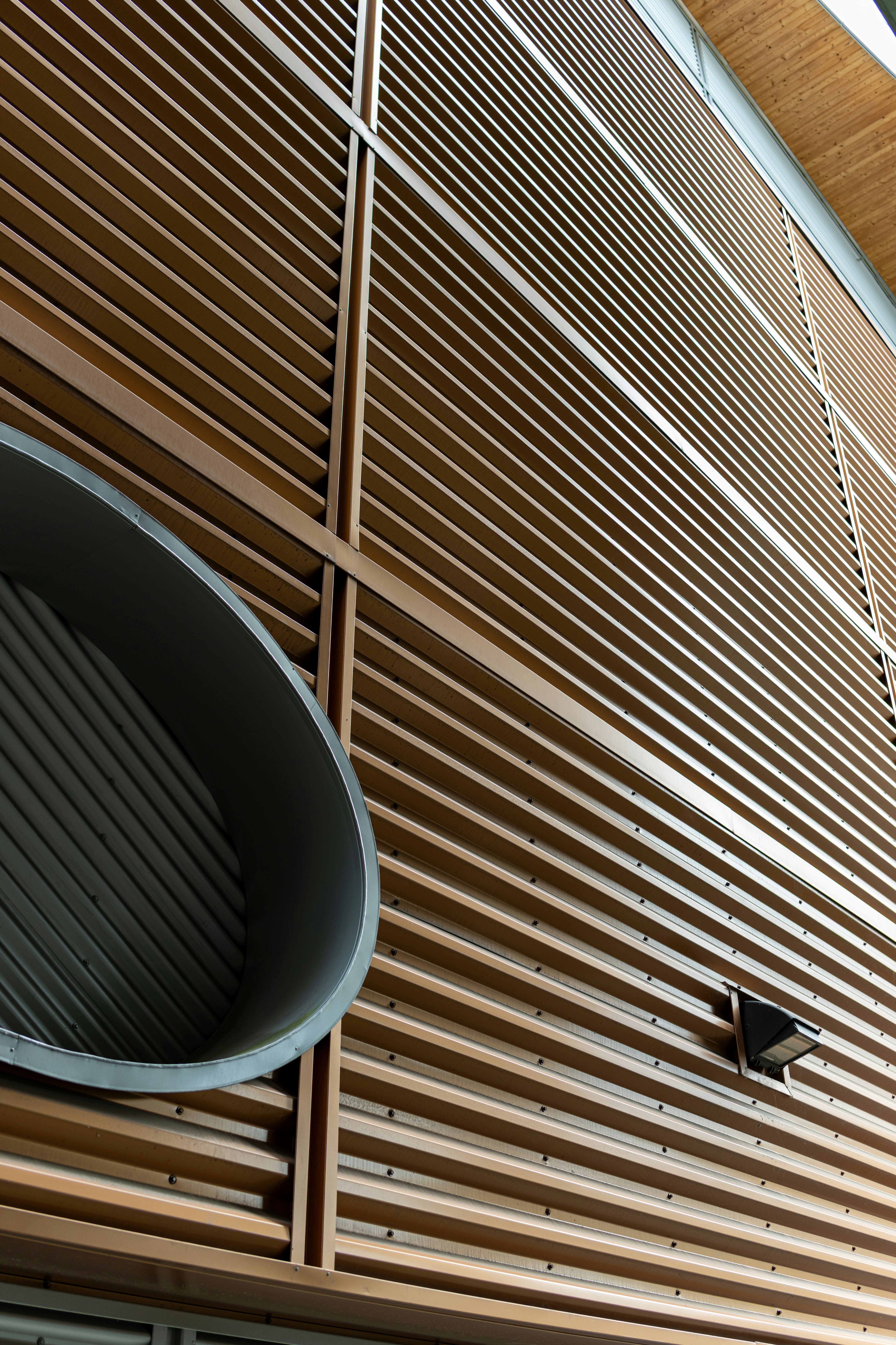Curved Vent Dlares Across a Copper Facade