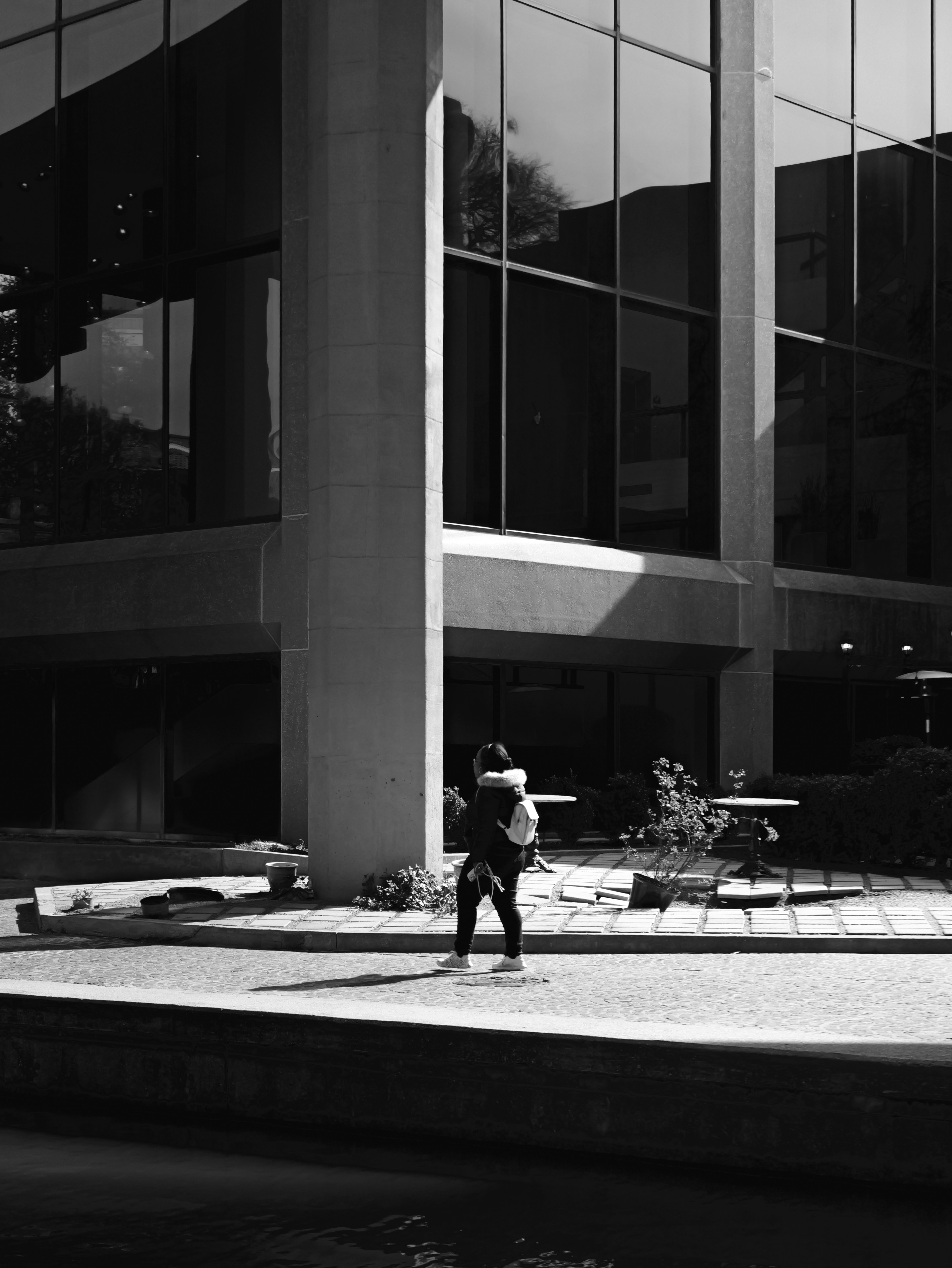 Oversized Glass, Quiet Stride: A Figure Walking the City Edge