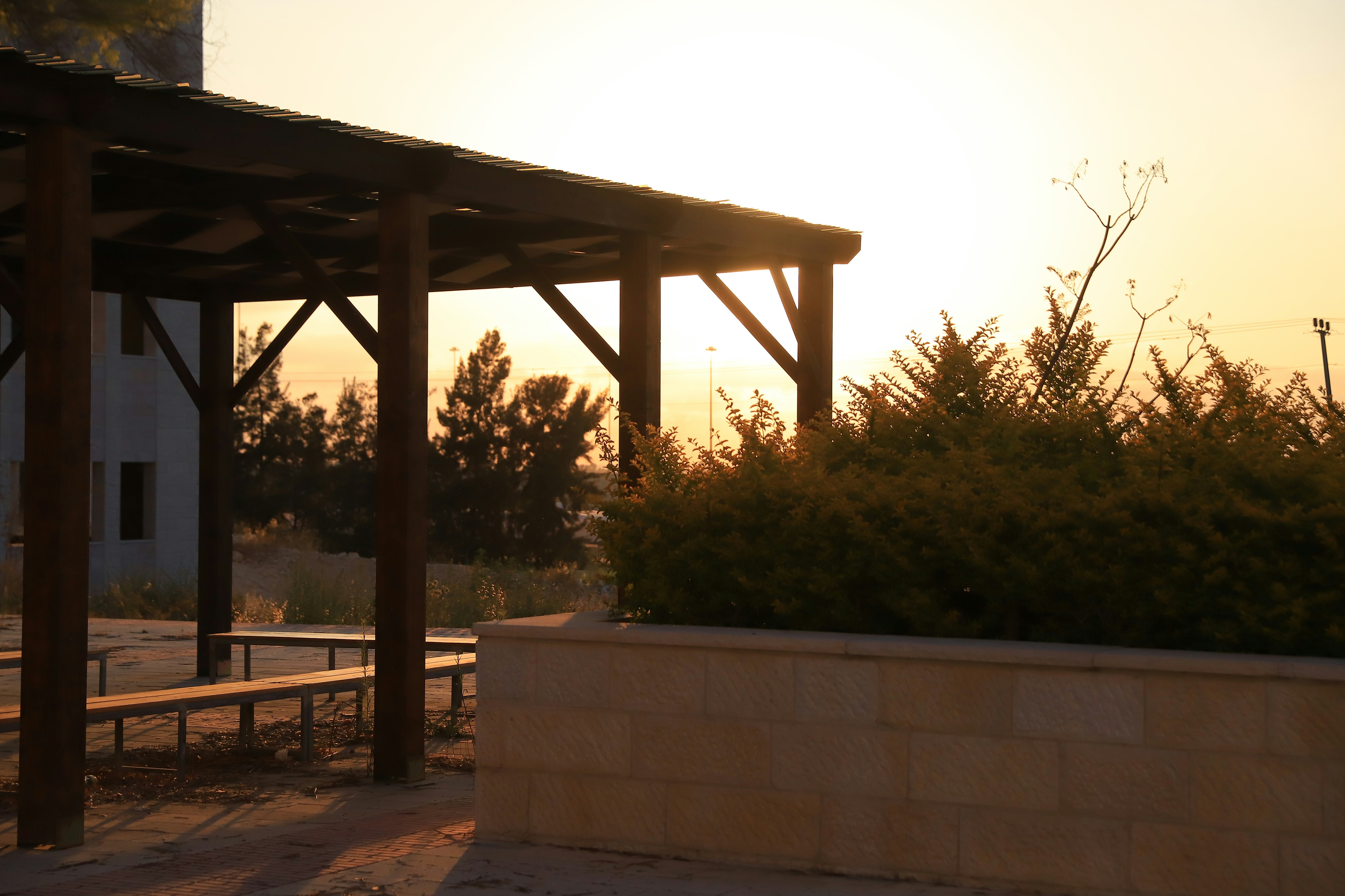 Sunset silhouette beneath a wooden pavilion over a stone ledge