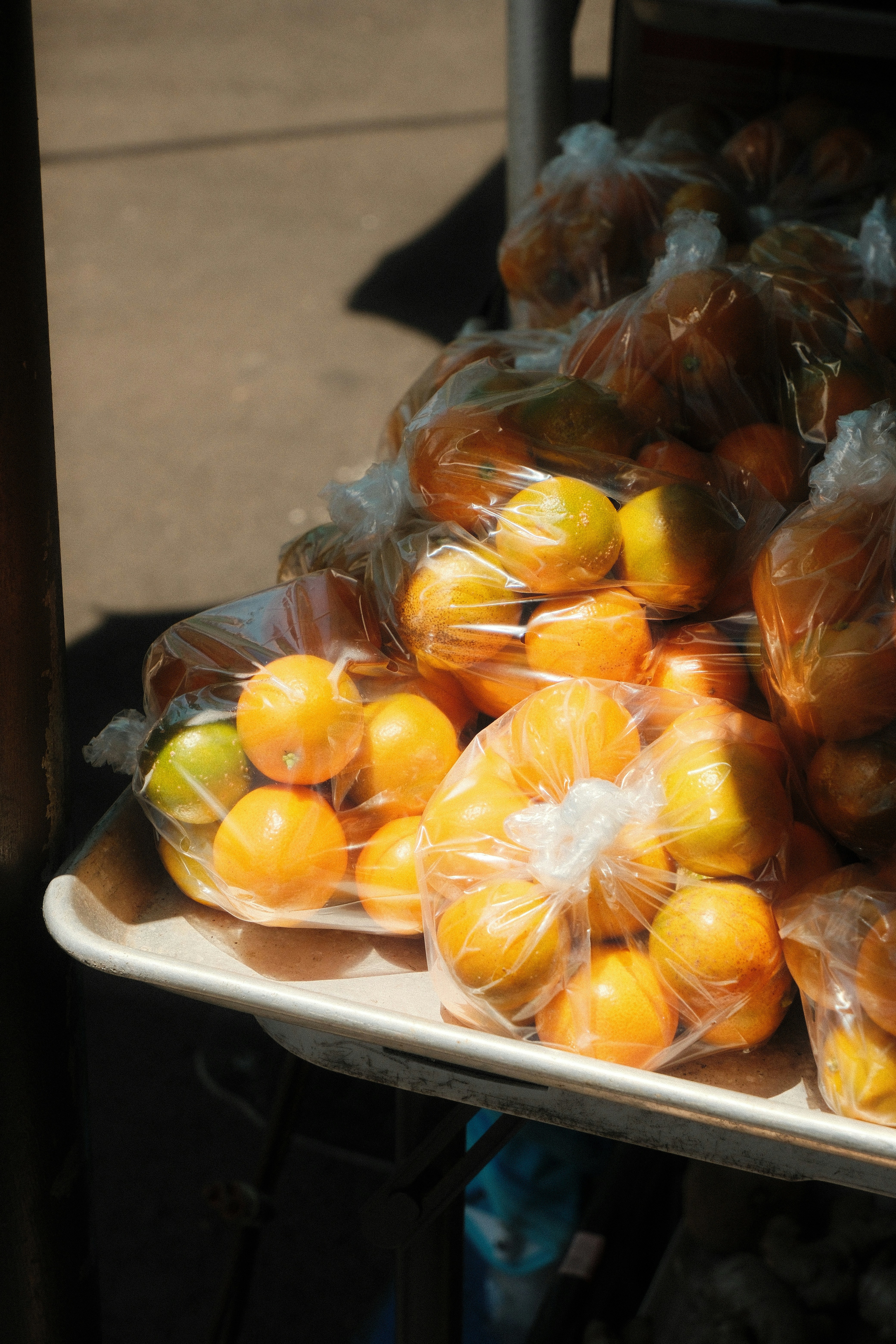 Bundles of Citrus Under Plastic at a Street Cart