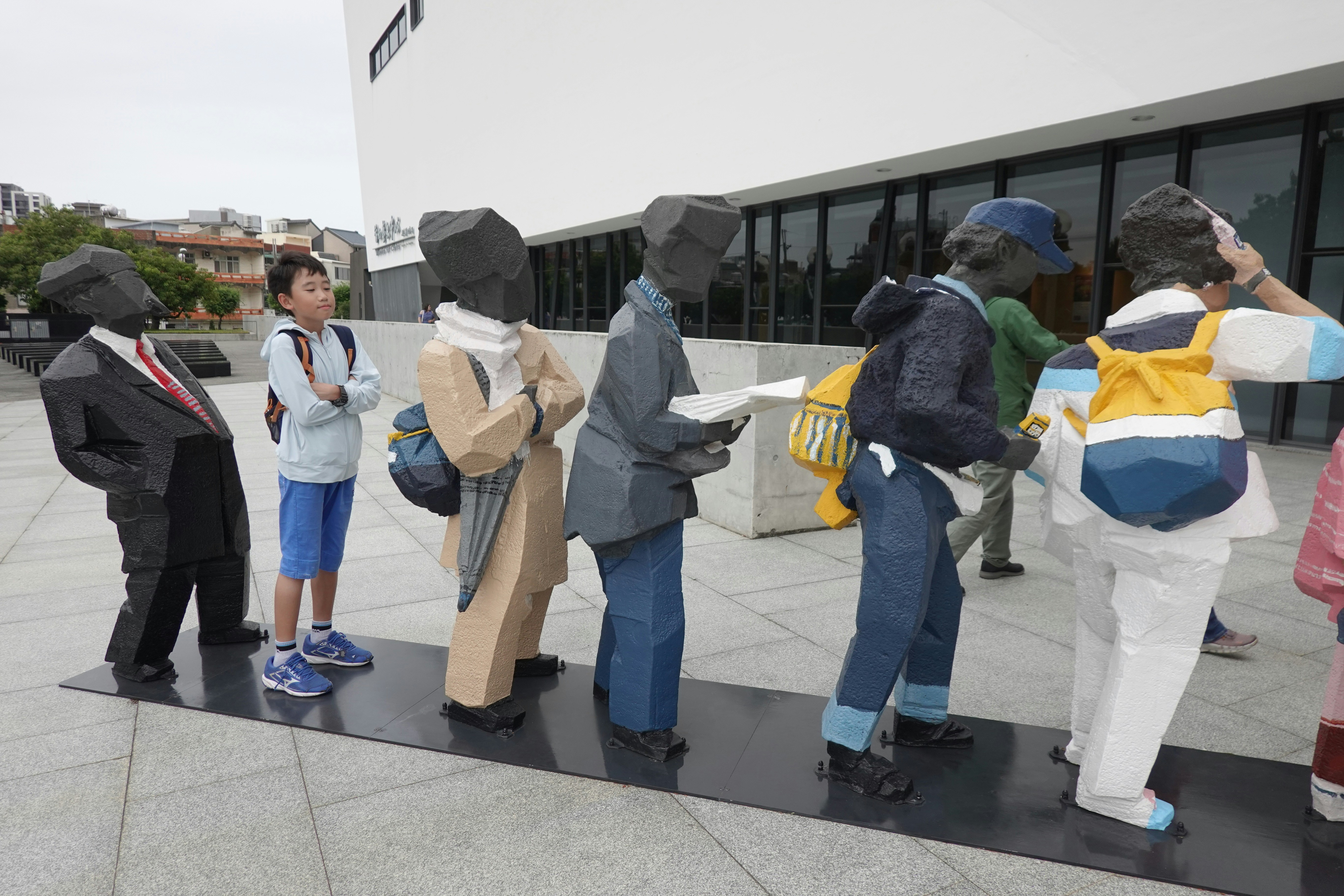 Ceramic-Colored Figures: A Line of Painted Statues Outside a Modern Building