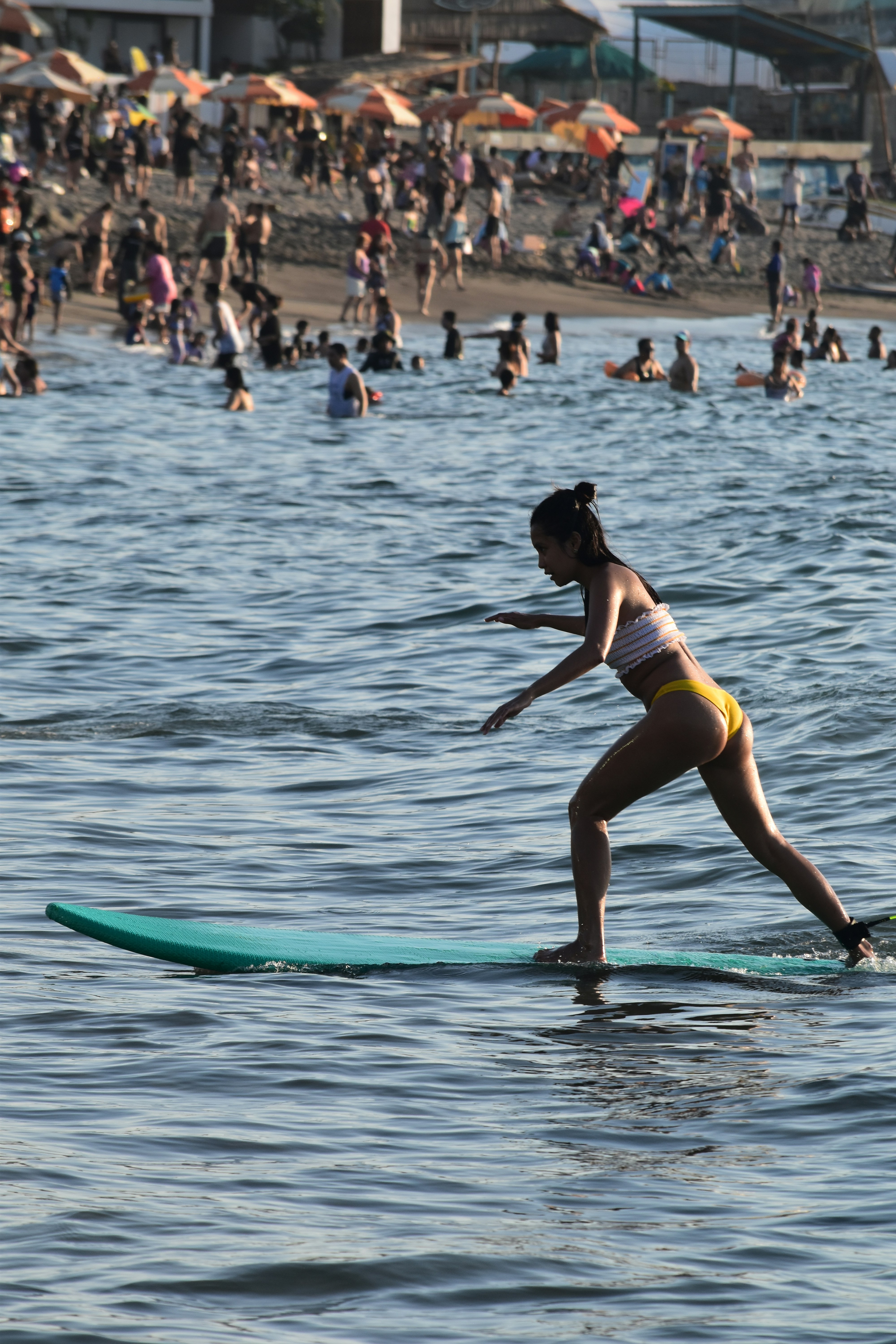 Balance on the Blue Wave: a surfer glides along a crowded shoreline