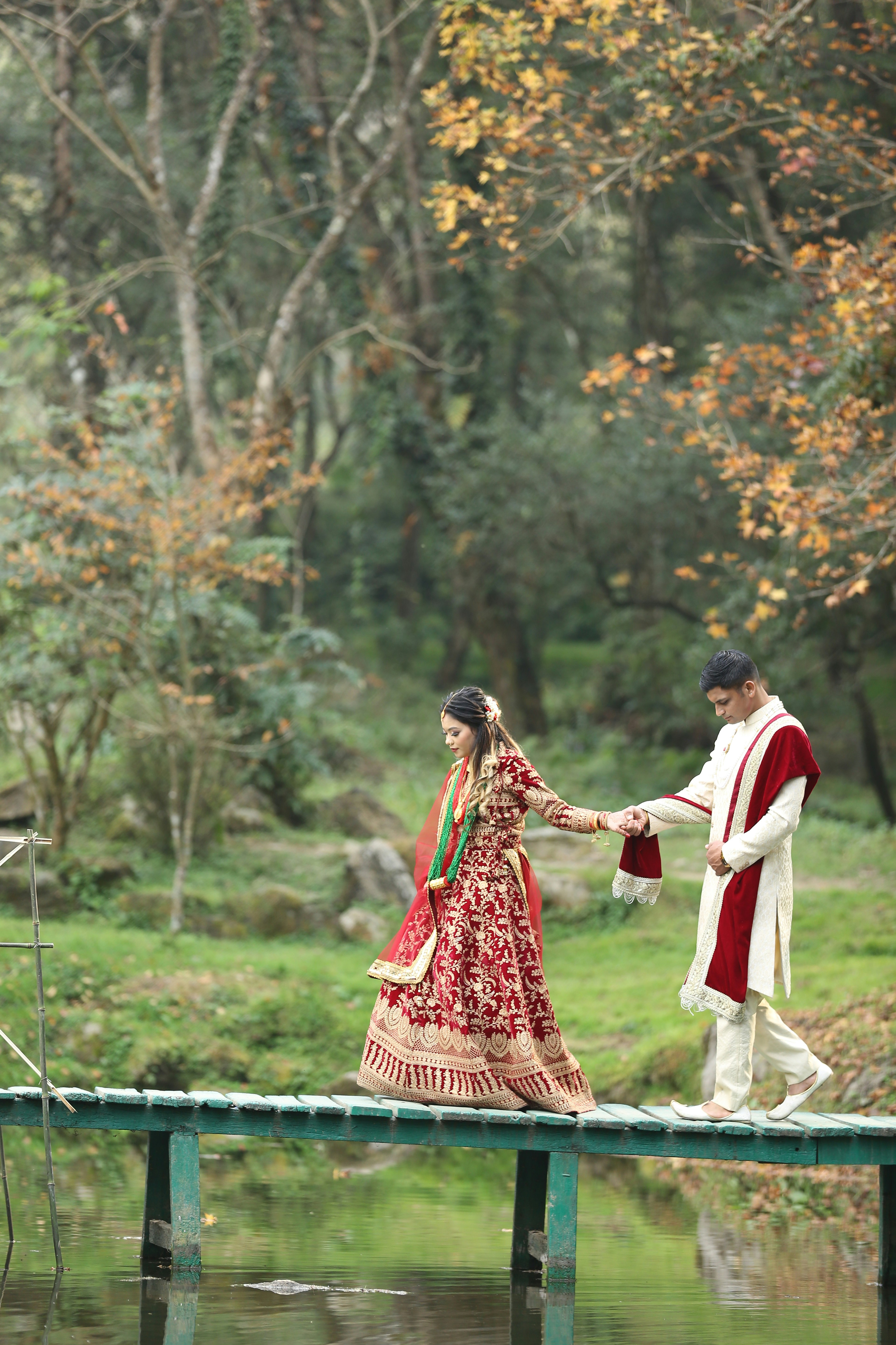 Bride and Groom Walk a Delicate Path Across a Narrow Bridge