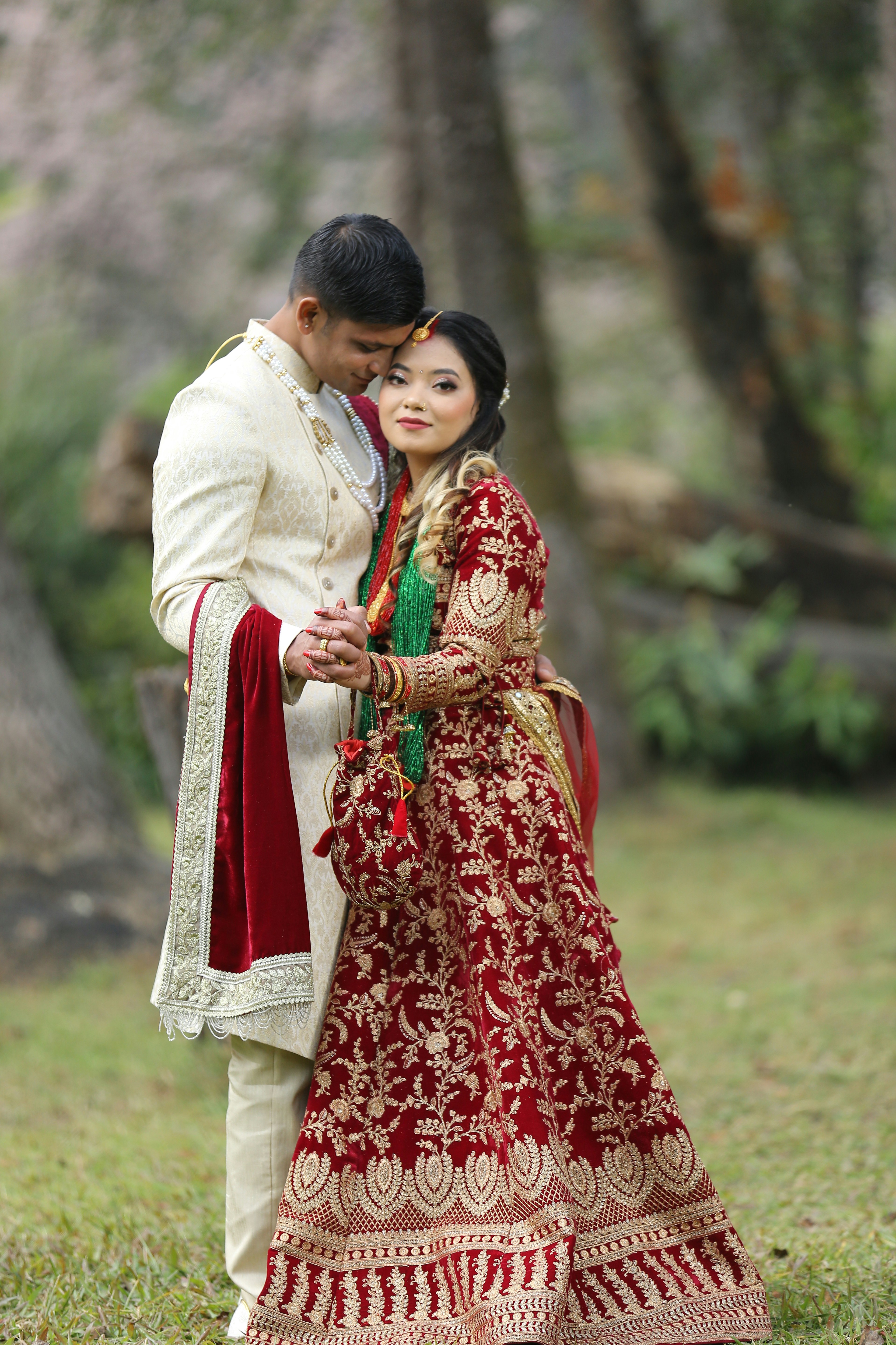 Bride and Groom in Romantic Golden Attire Embrace in a Park
