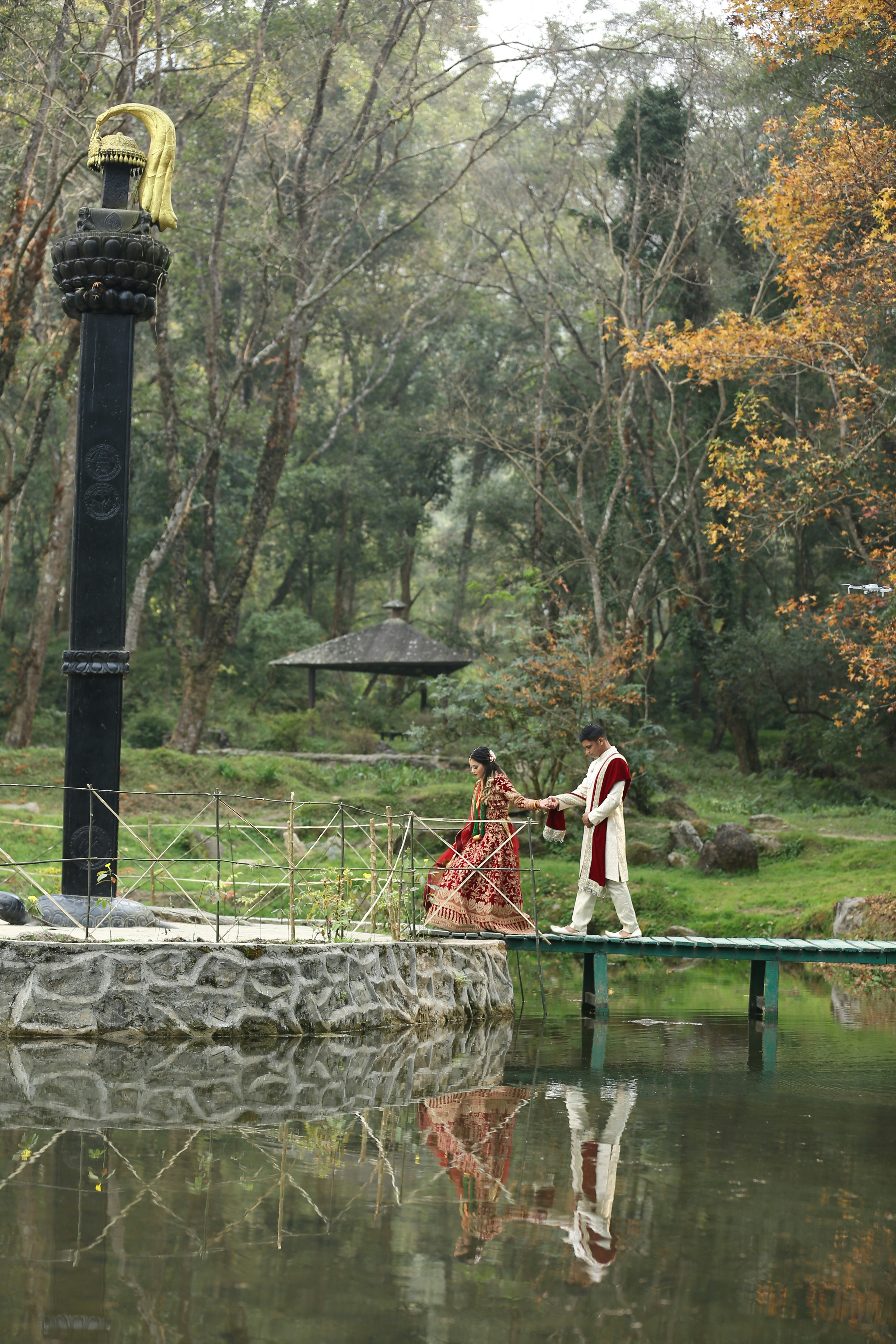 Bridge of Dawn: A Couple Crosses in Traditional Attire