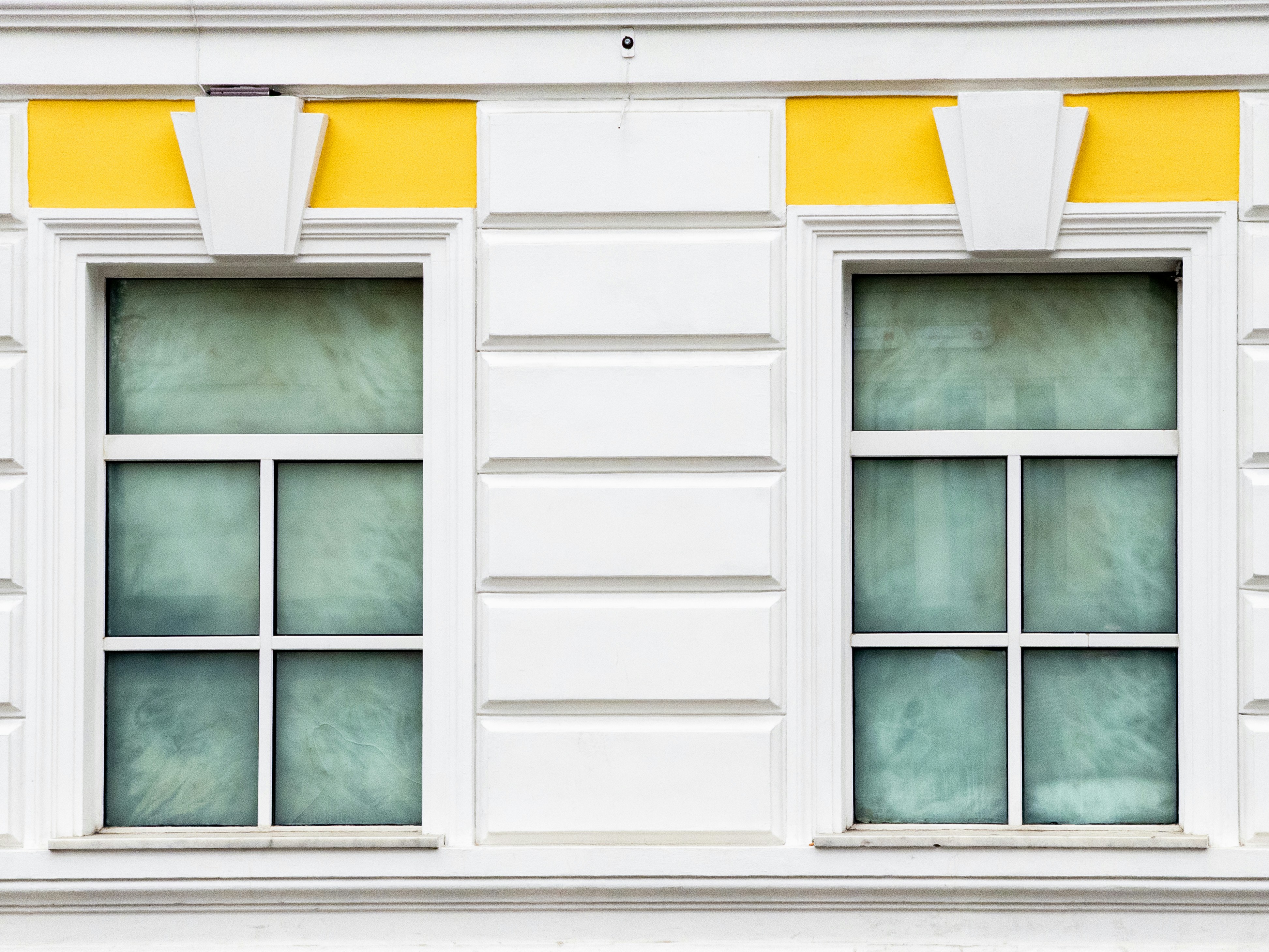 Symmetry in Yellow and Slate: Twin Windows on a White Facade