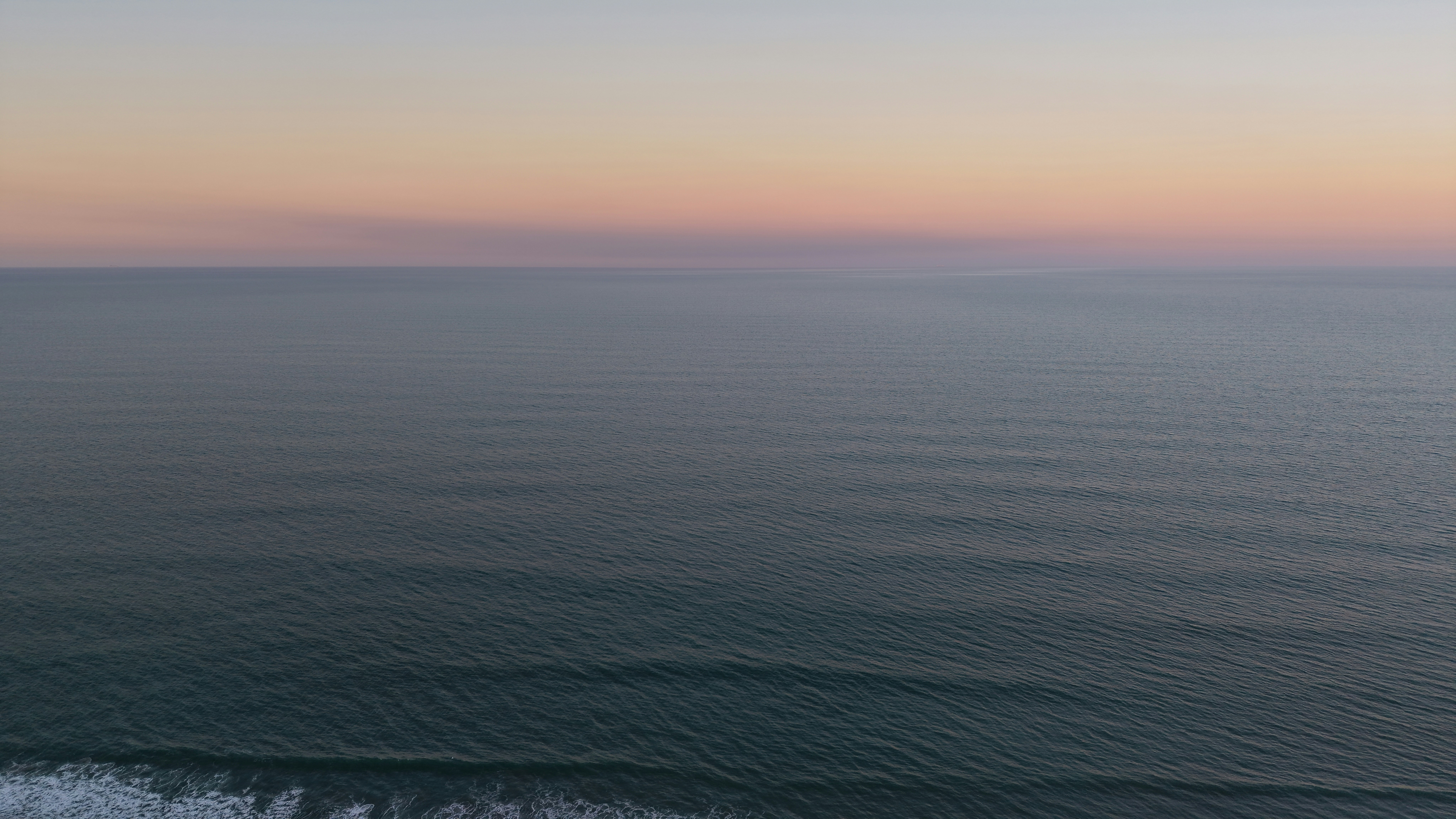Dawn over a tranquil sea: pastel horizon and gentle waves