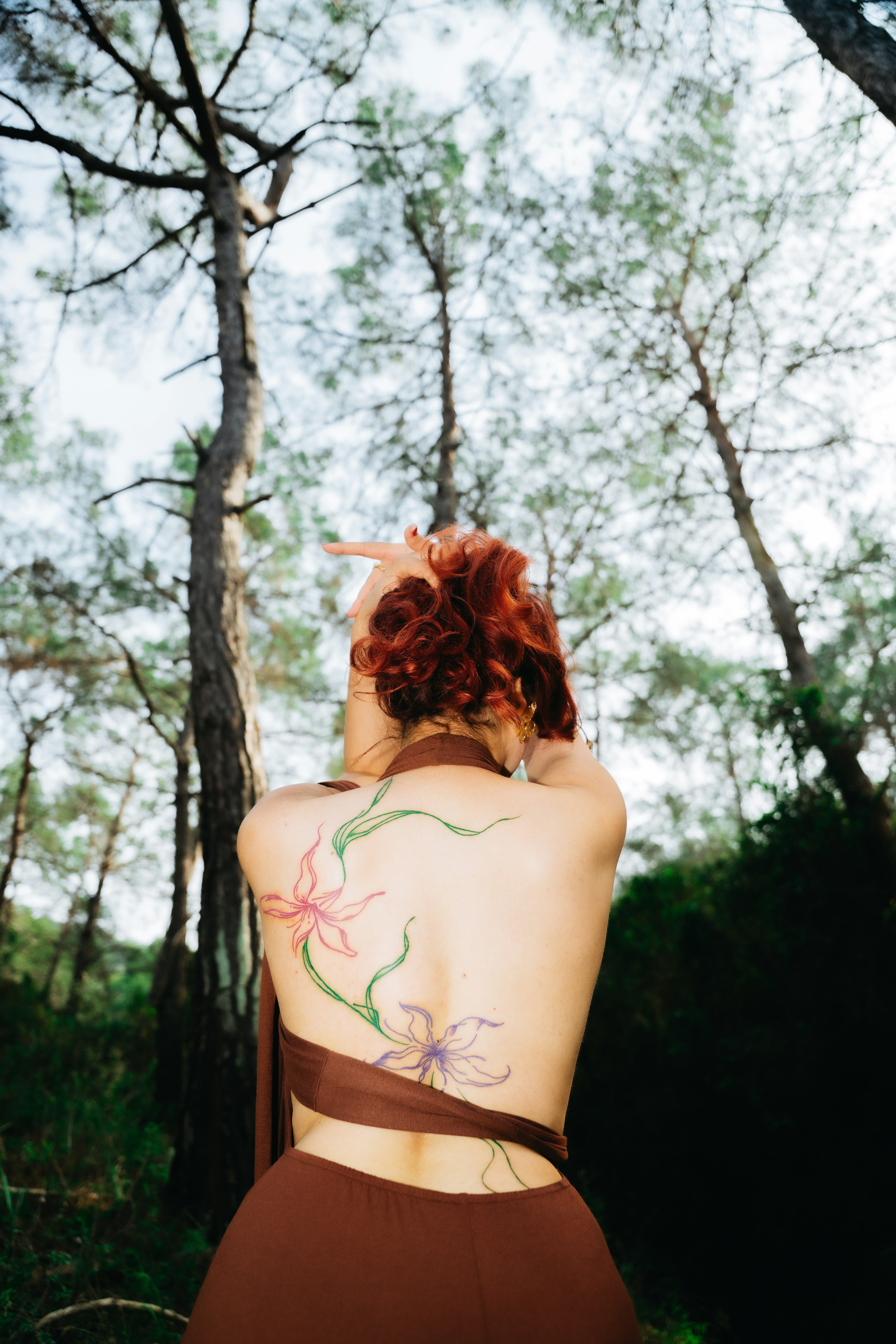 Back-View Portrait: Inked Florals Blooming on Bare Back Amid Pines