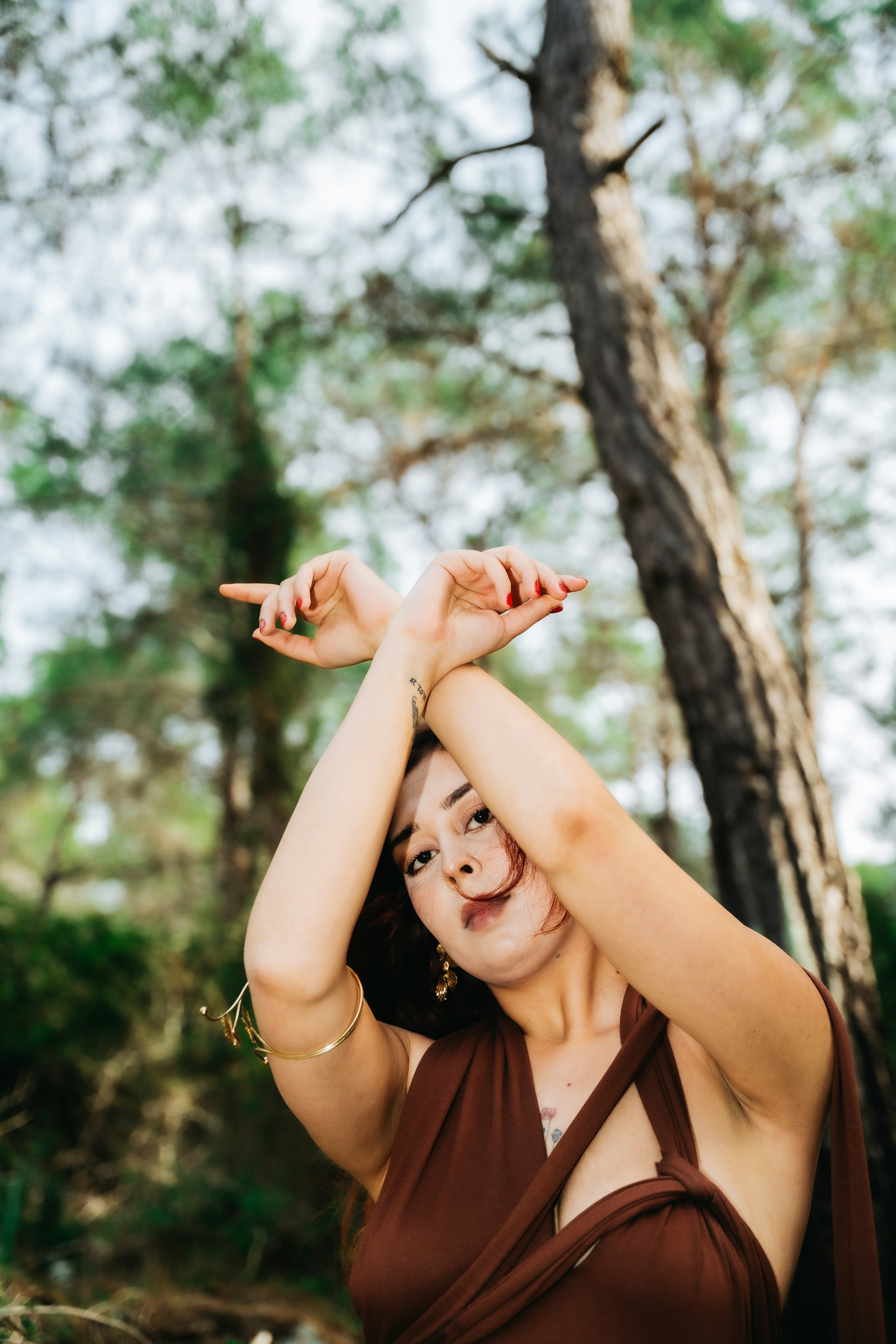 Crossed forearms in a sunlit forest portrait