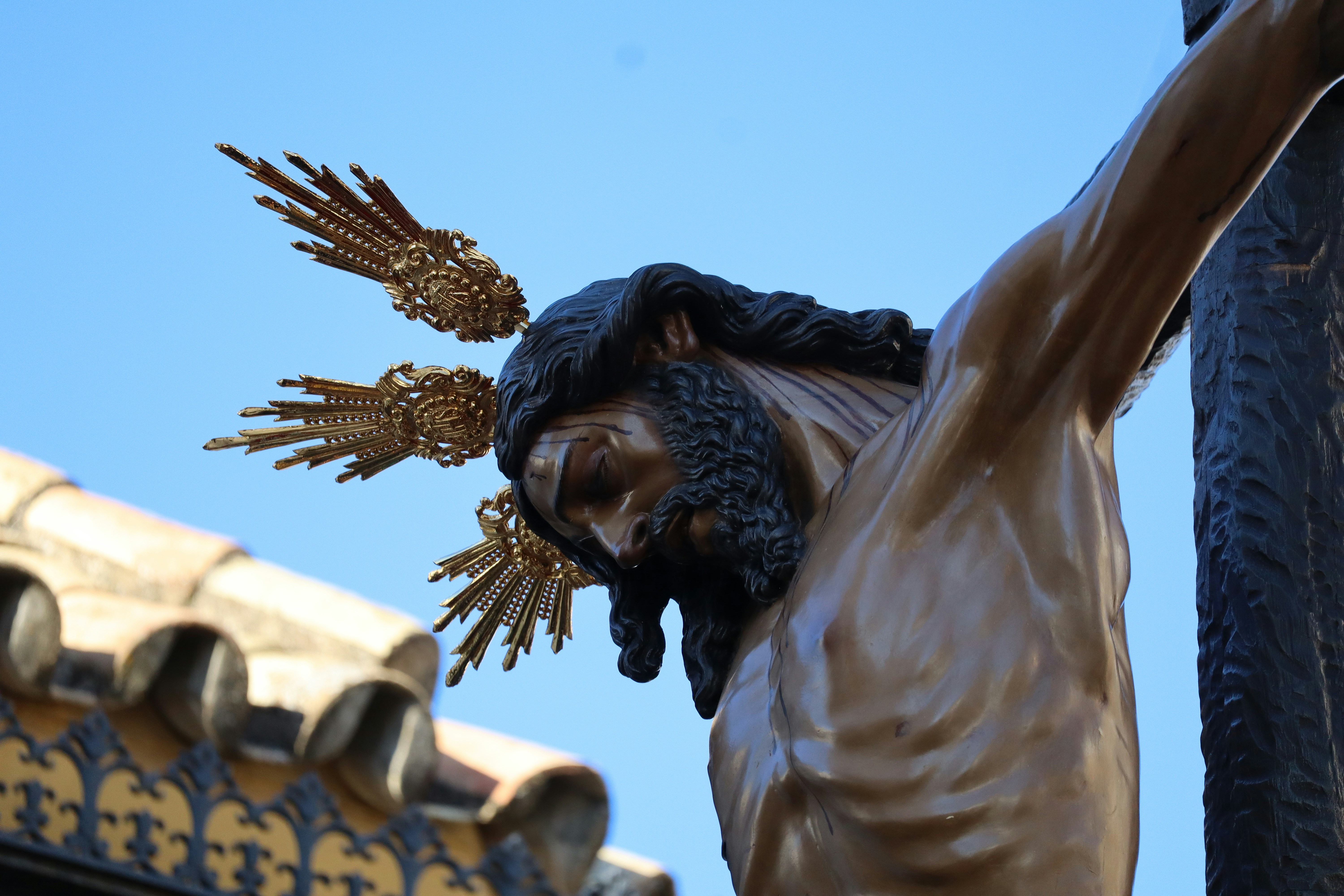 Cruciform Gaze: A Bronze Christ Beneath a Clear Sky